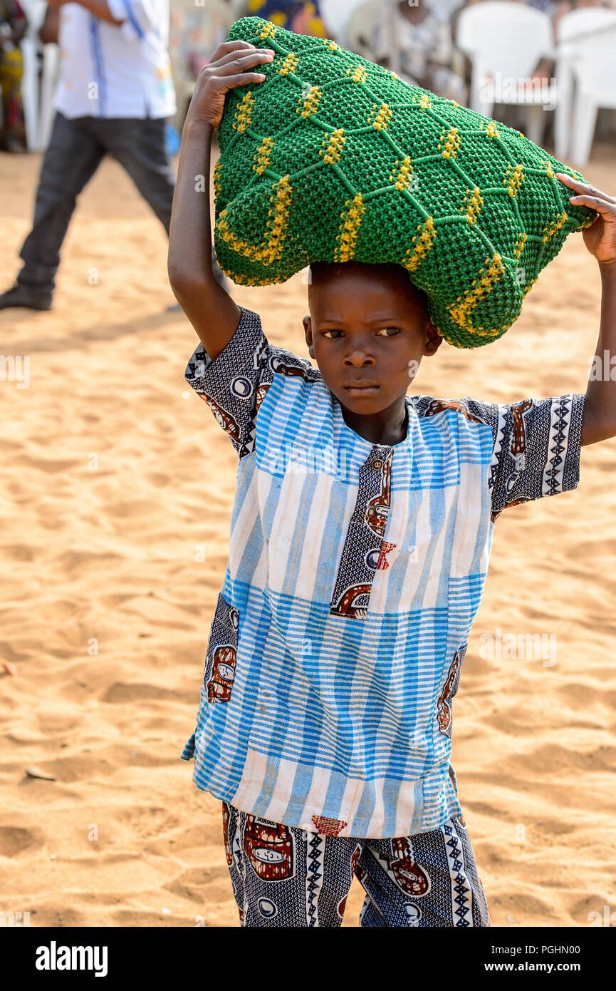 OUIDAH, BENIN - Jan 10, 2017: Unidentified Beninese little boy carries ...