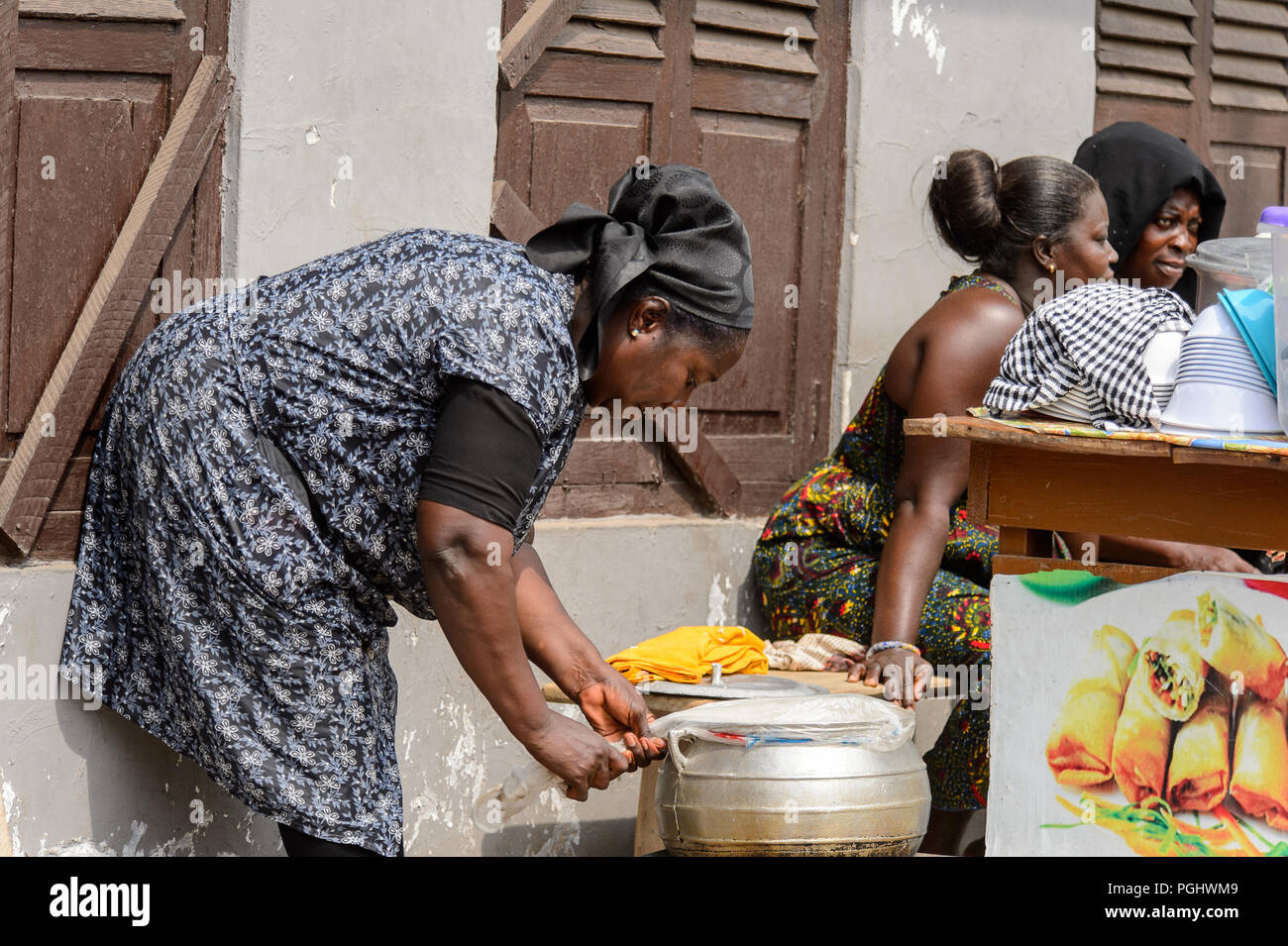 KUMASI, GHANA - Jan 16, 2017: Unidentified Ghanaian woman bends down to ...