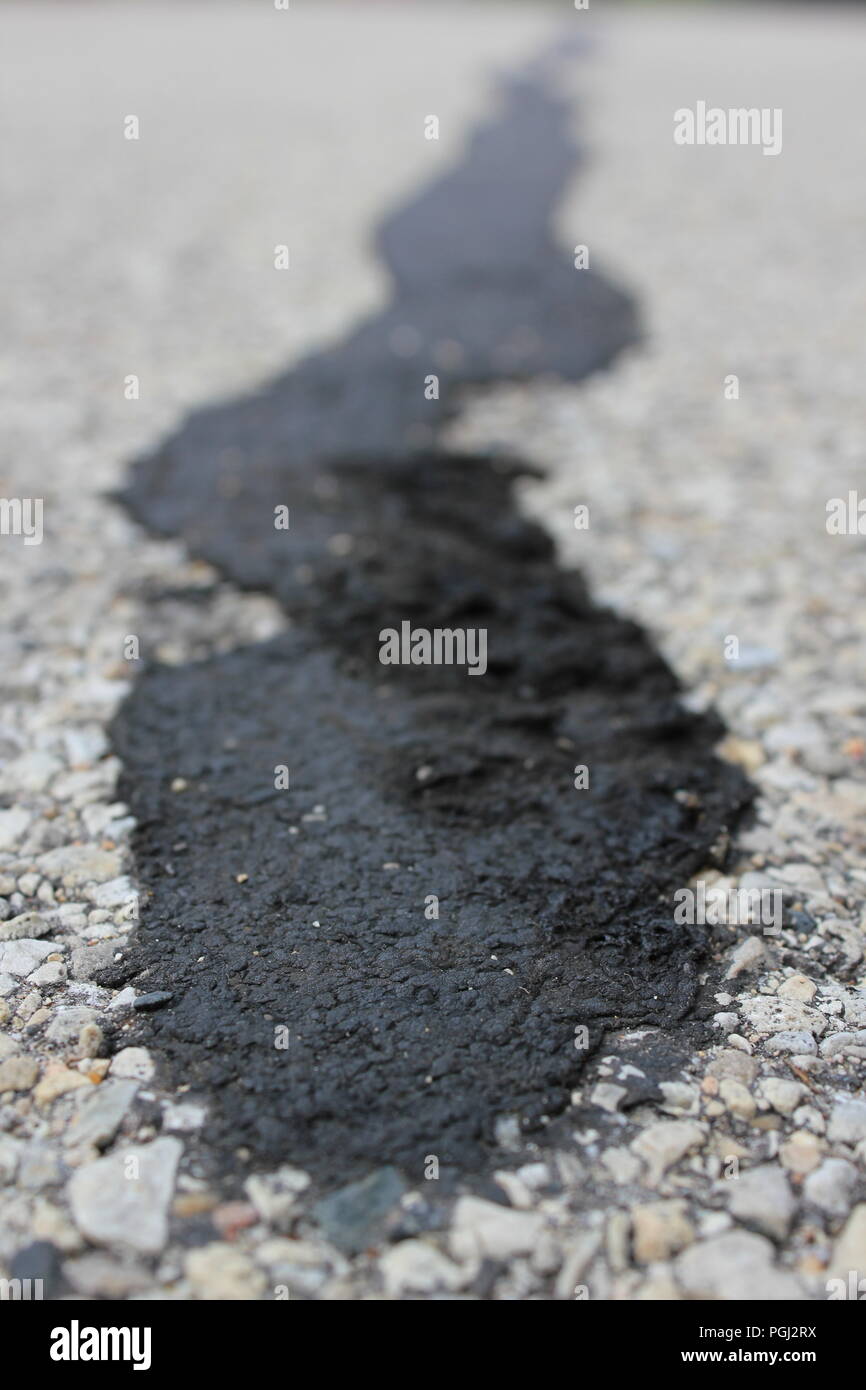 A pavement surface fixed by the application of a black tar Stock Photo ...