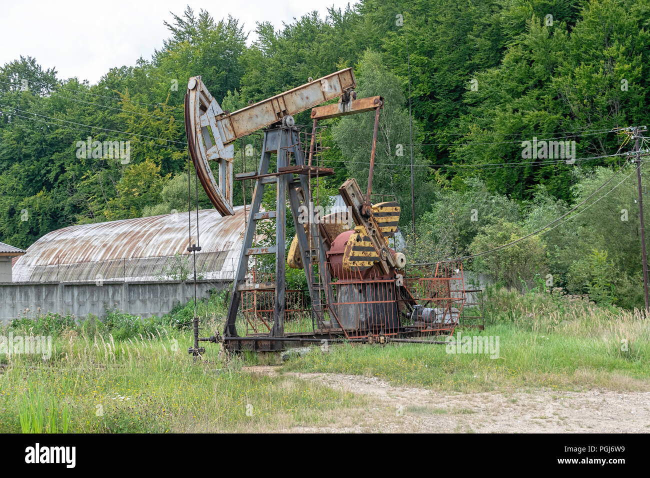 Oil rig is pumping the oil with beautiful landscape on the background ...