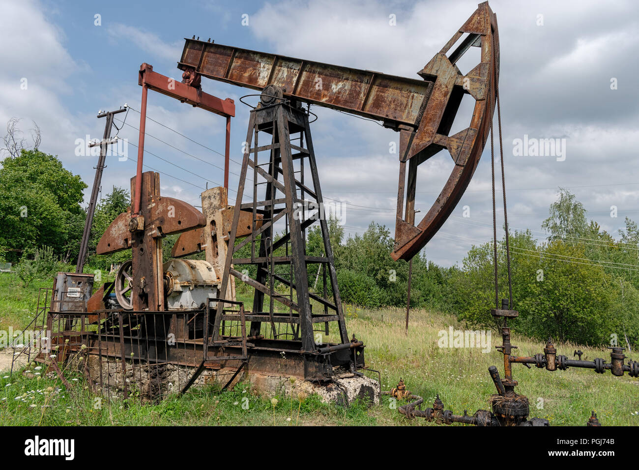 Oil rig is pumping the oil with beautiful landscape on the background ...