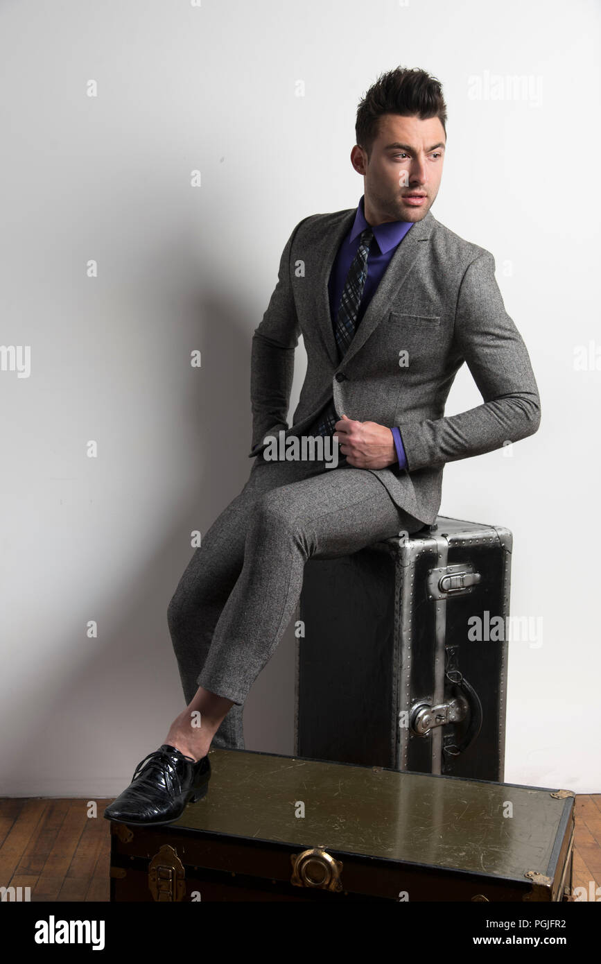 A handsome stylish man sitting on steamer trunks Stock Photo - Alamy