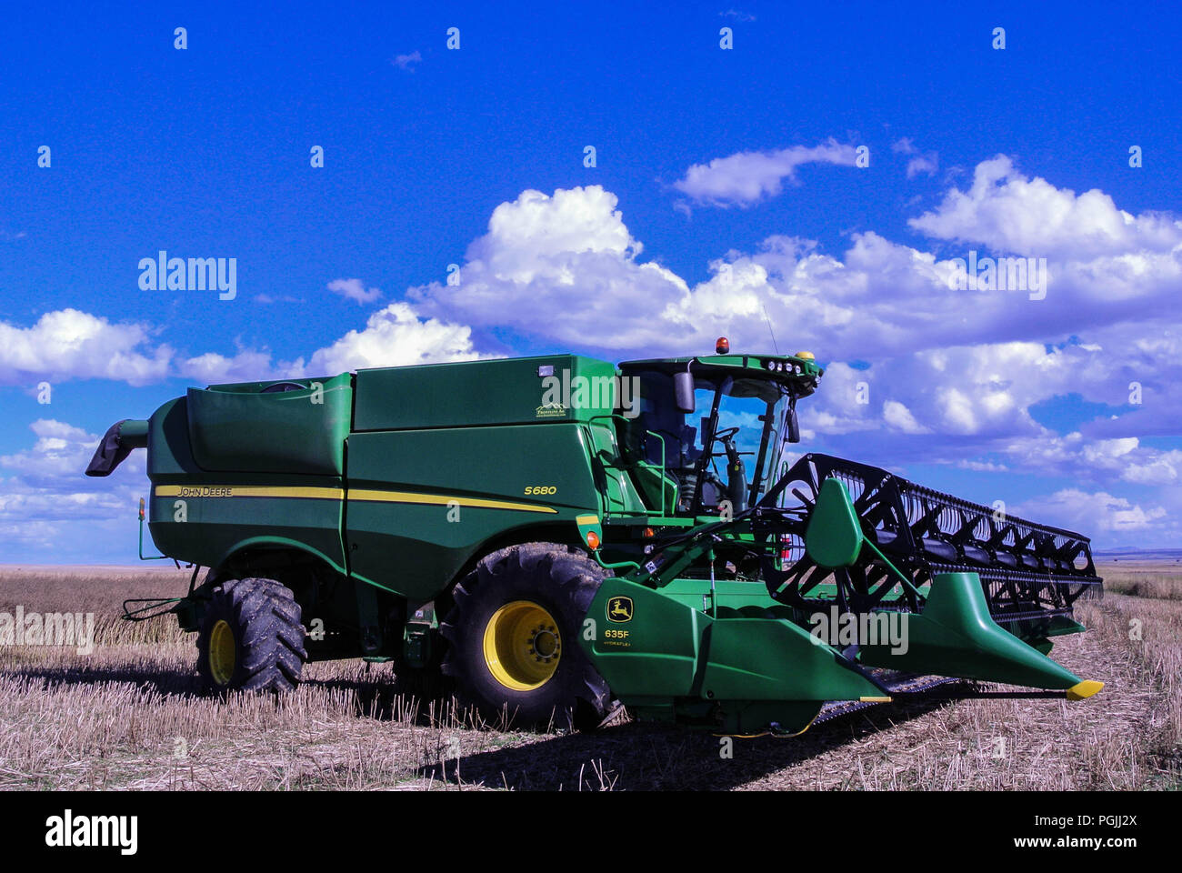 John Deere combine with a flex header sitting on the edge of a field ...