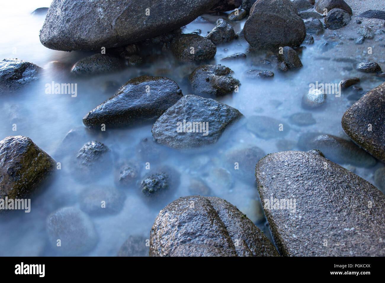 Rocks in blue sea water long exposure Stock Photo - Alamy