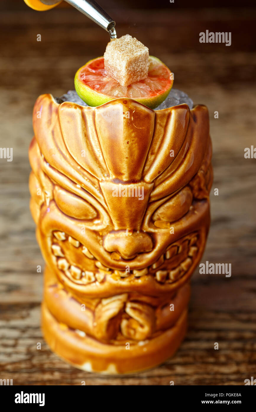 Cocktail zombie in a glass of tiki, exotic cocktail with fire on a bar ...