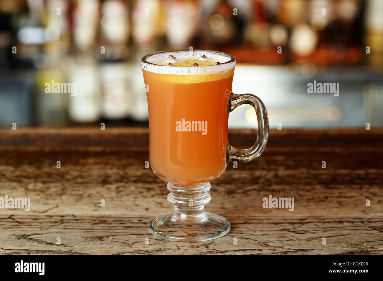 Hot alcoholic grog with orange and seasoning cloves on a wooden bar ...