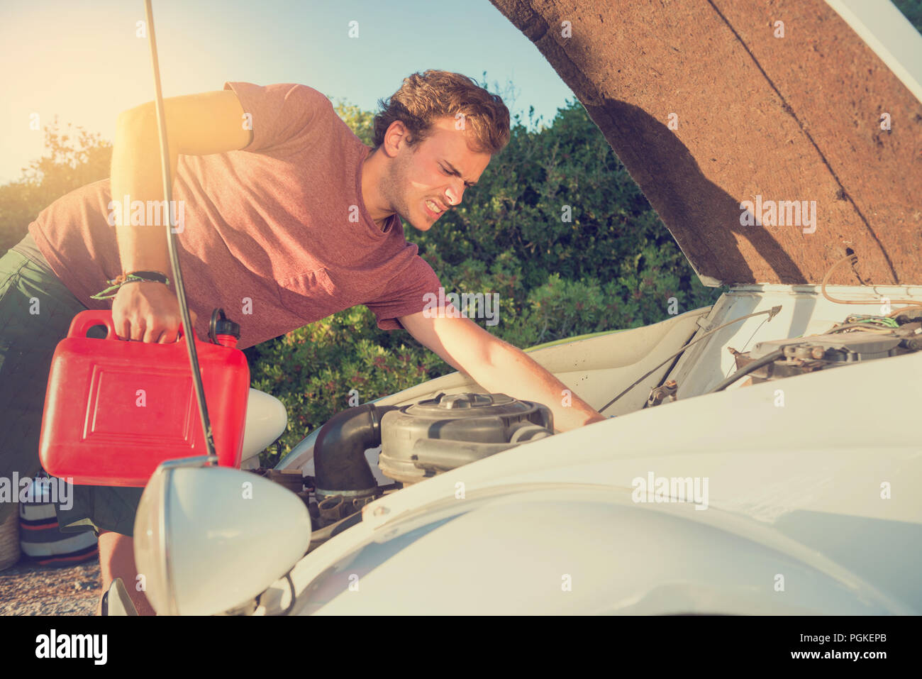 Young man looking at the engine of a broken car Stock Photo - Alamy