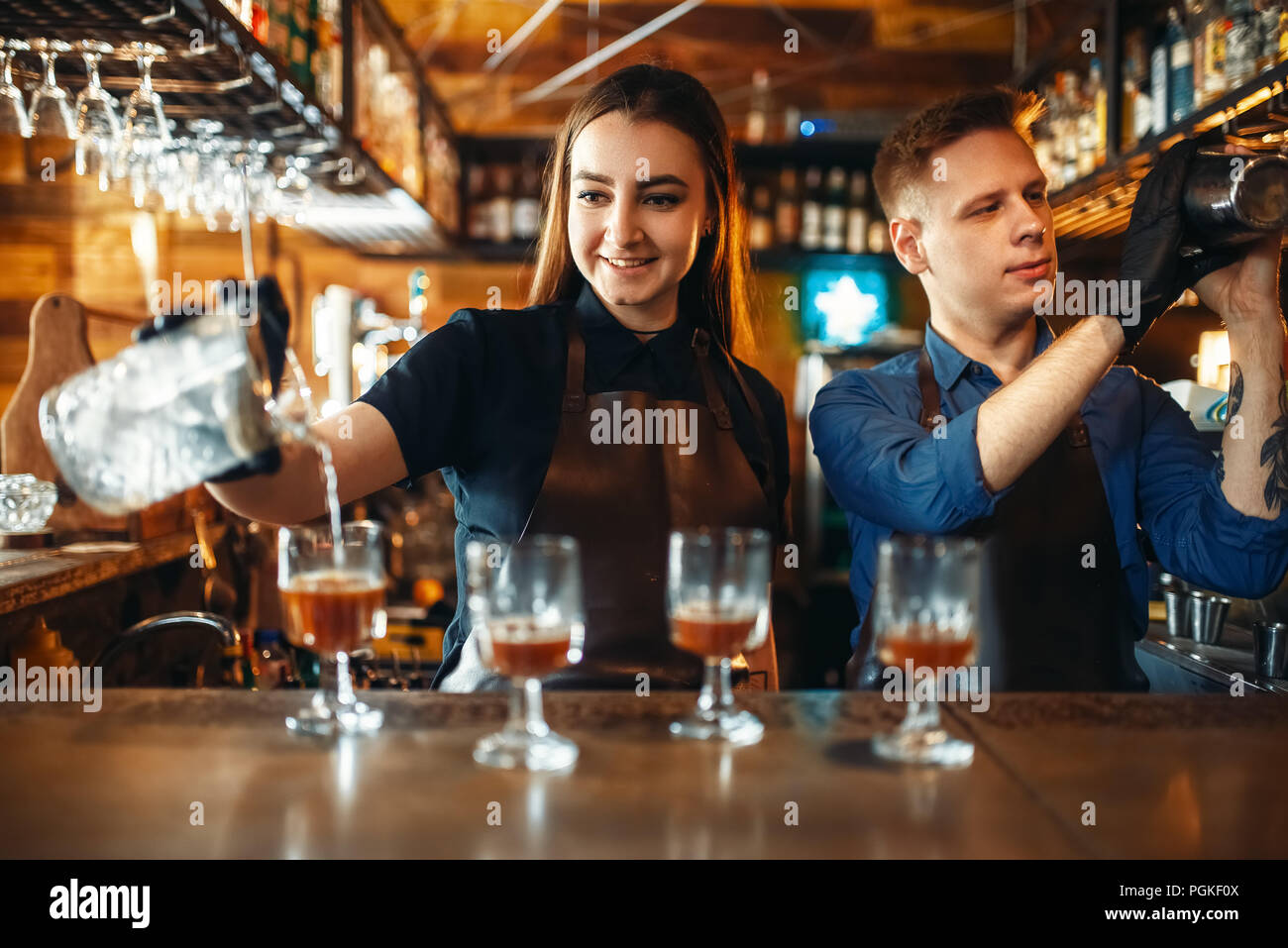 Male and female bartender at the bar counter. Alcohol drink preparation ...