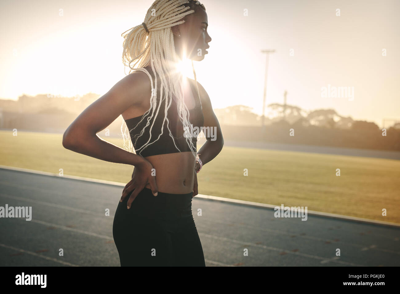 Side view of female athlete standing on an all-weather running track ...