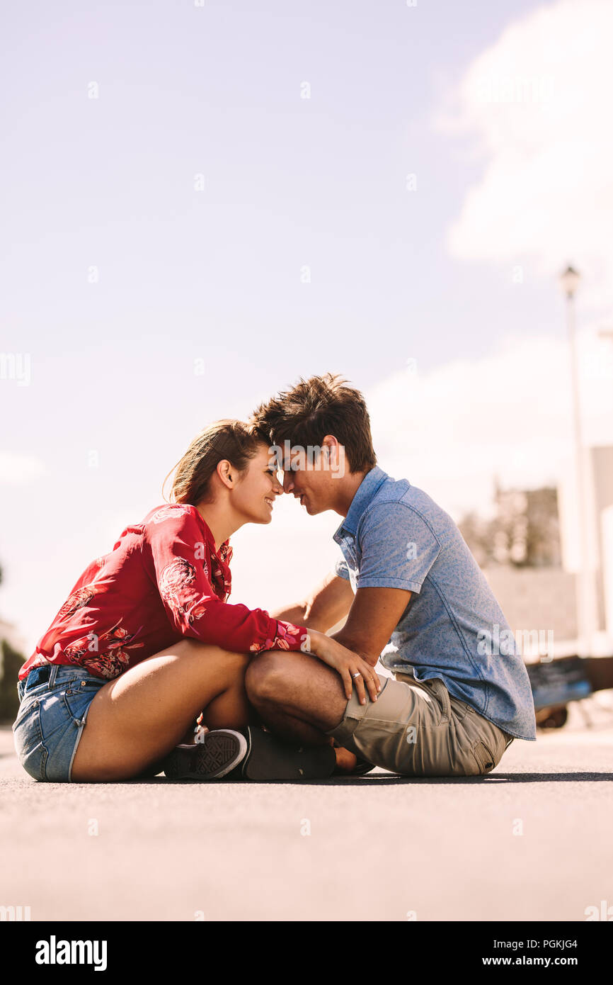 Romantic Couple Sitting On The Ground Together Touching Their Heads