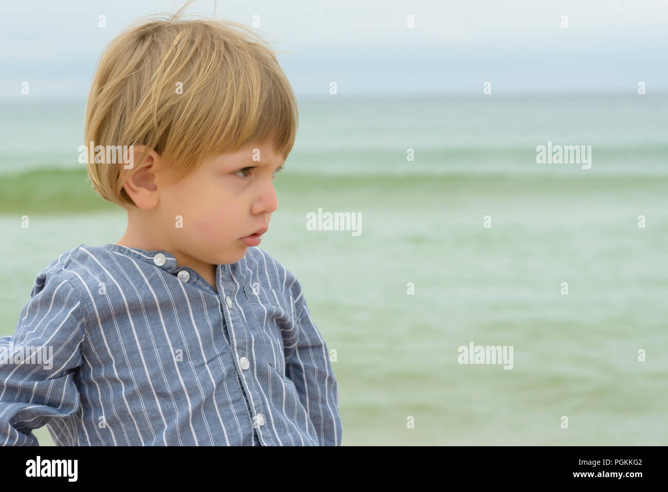 Cute upset boy looking serious on seaside Stock Photo - Alamy