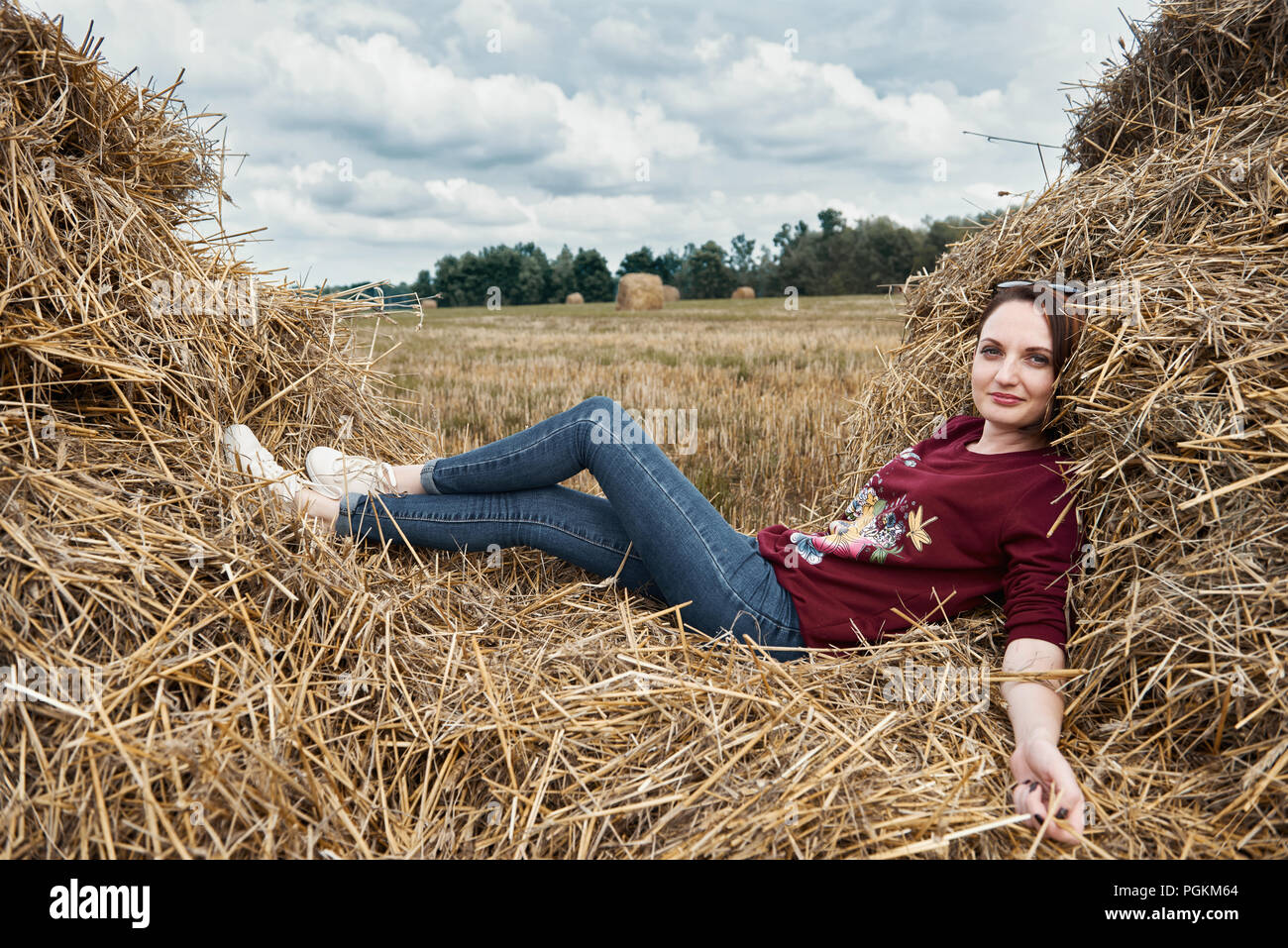 young girl having fun in the field, lying on a haystack Stock Photo - Alamy