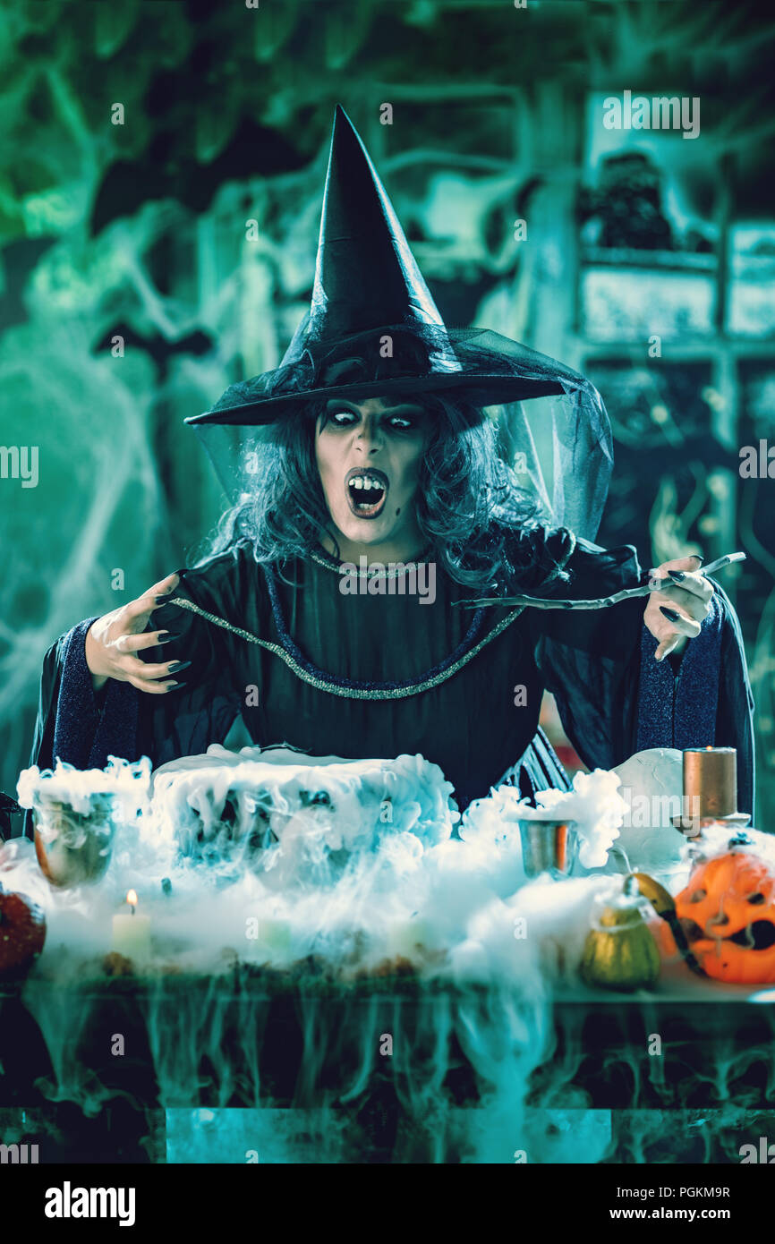 Witch with awfully face and hat on her head in creepy surroundings full ...