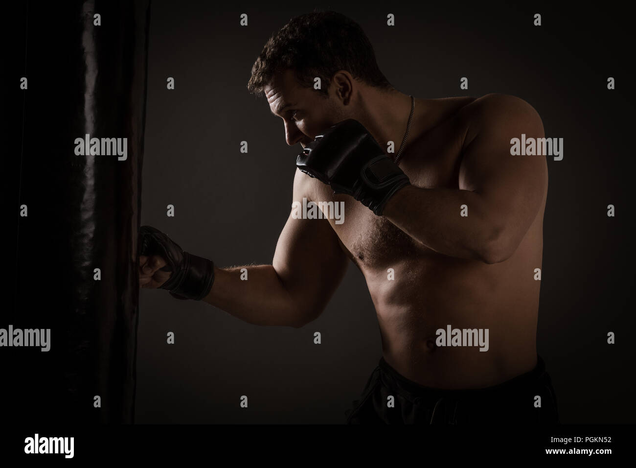 Young muscular man punching the boxing bag Stock Photo - Alamy