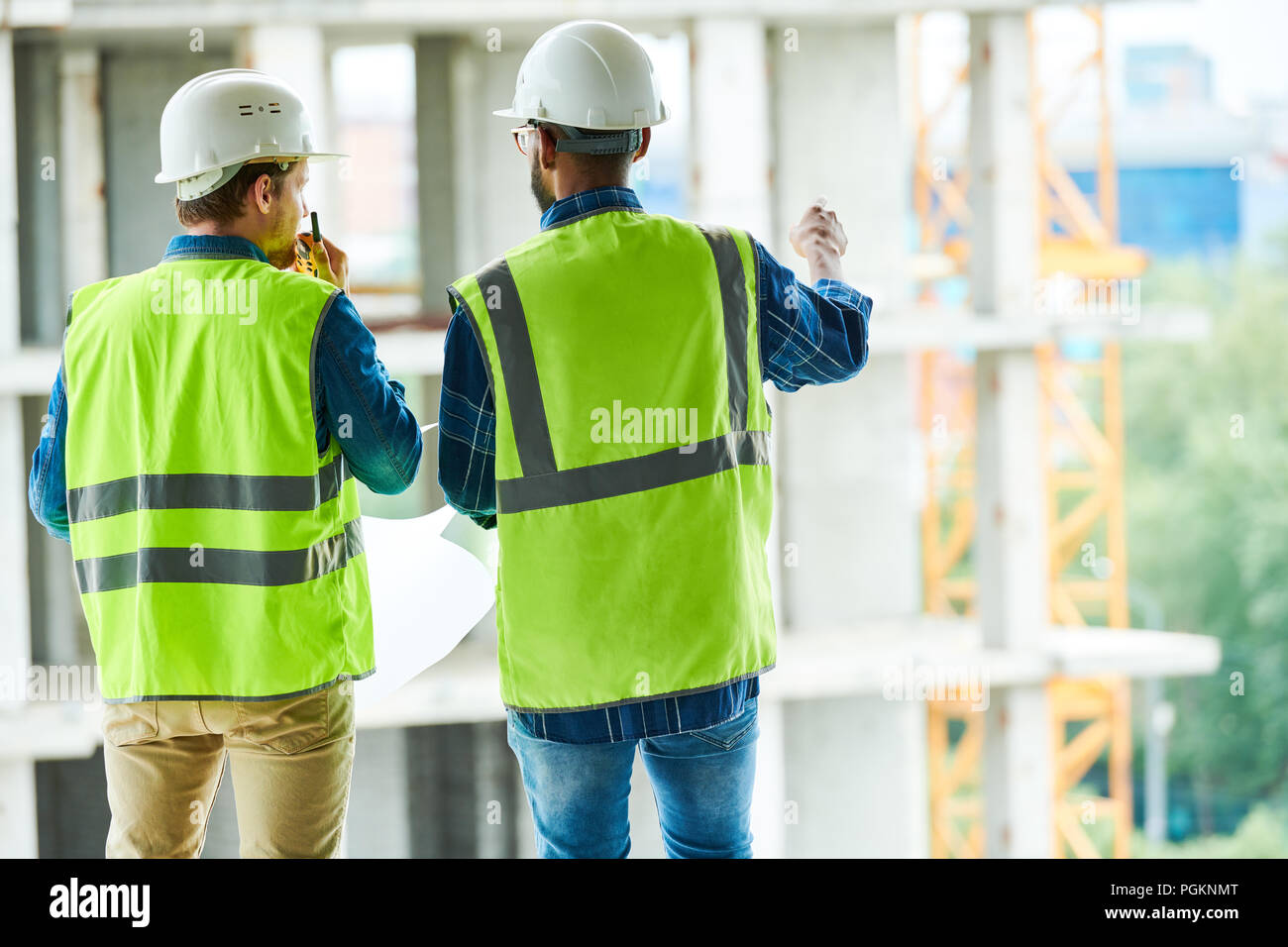 Back view portrait of two construction workers wearing hardhats and ...