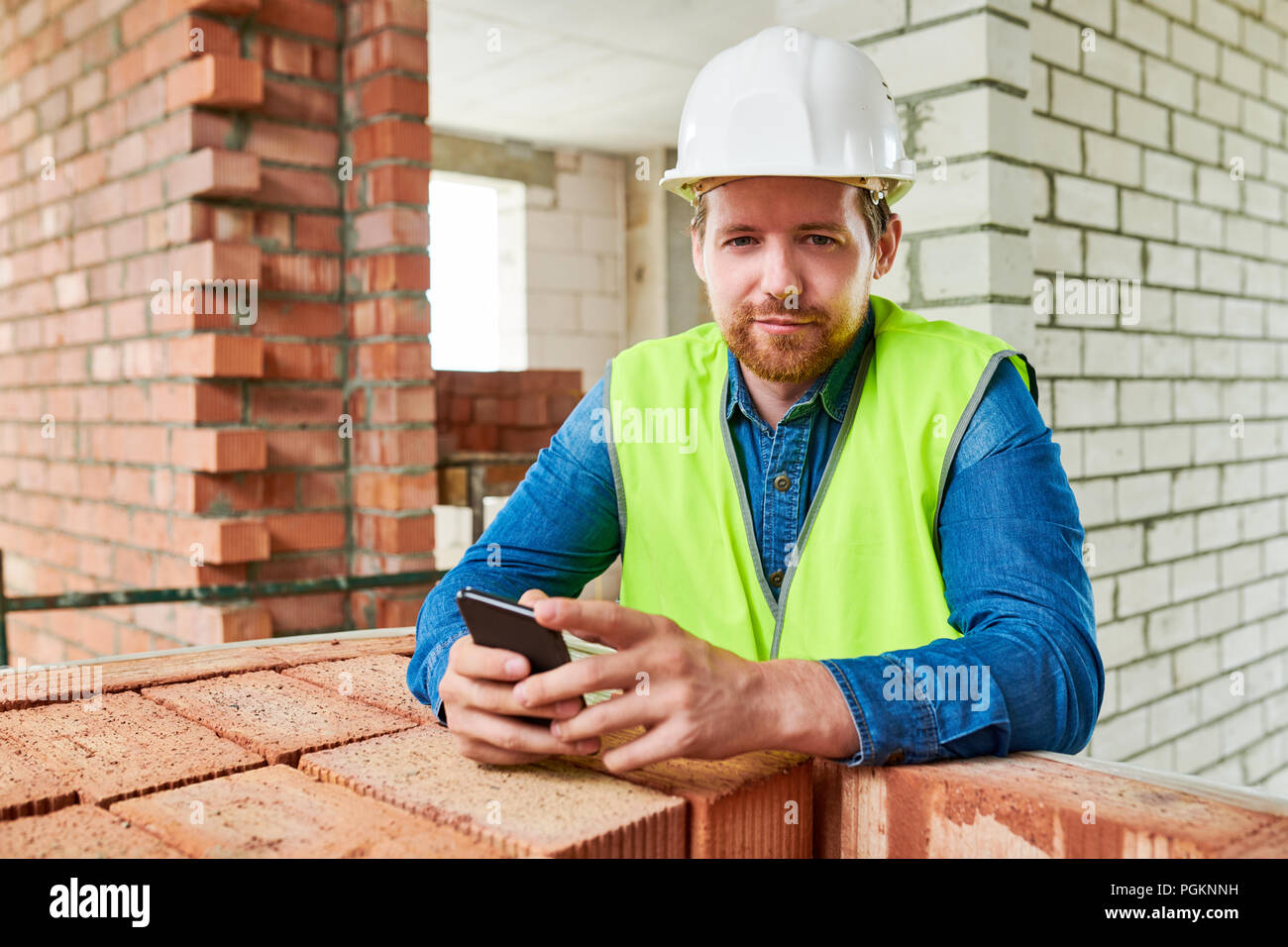 Portrait of bearded construction worker smiling at camera while leaning ...