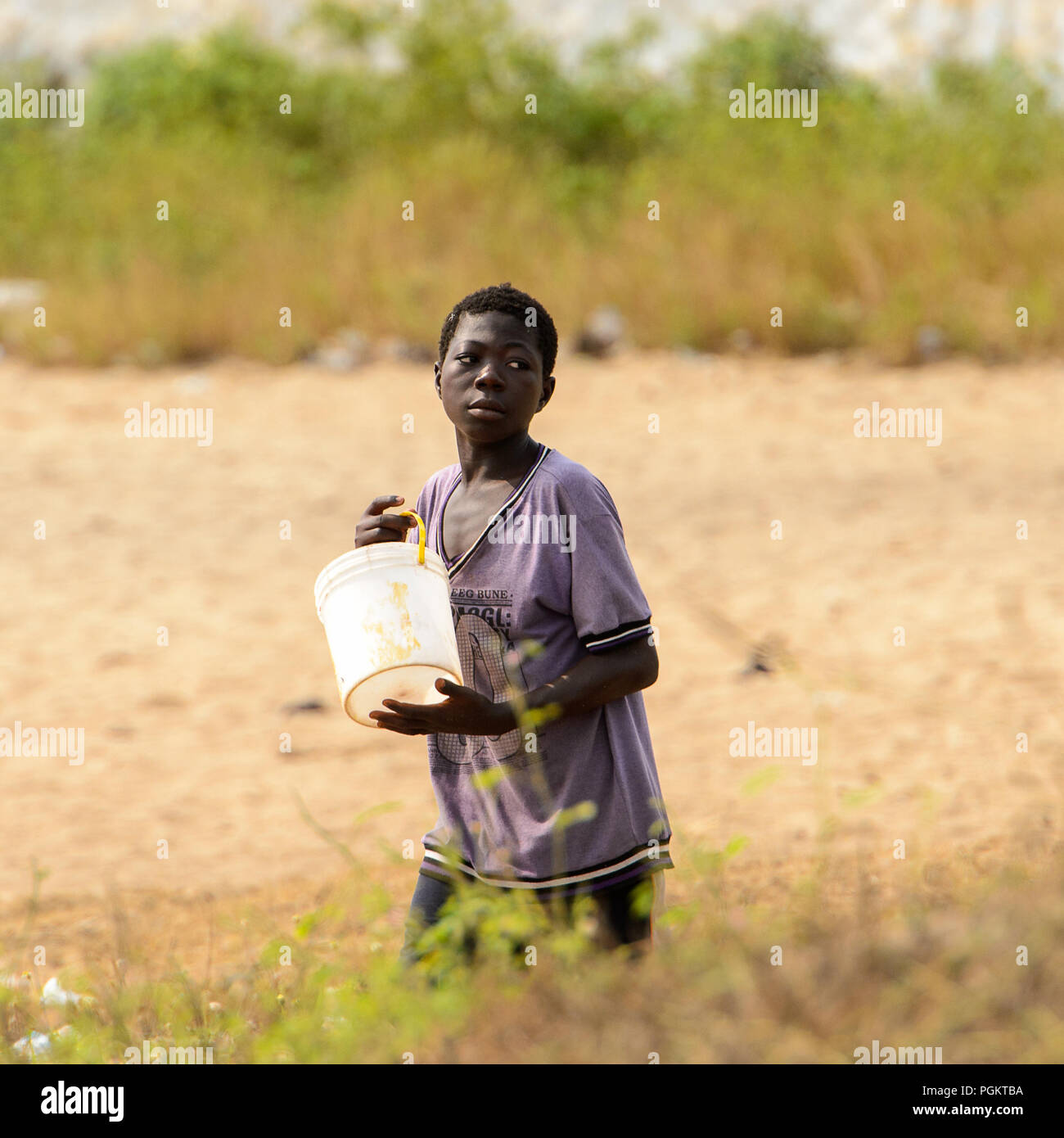 ELMINA, GHANA -JAN 18, 2017: Unidentified Ghanaian boy carries a bucket ...