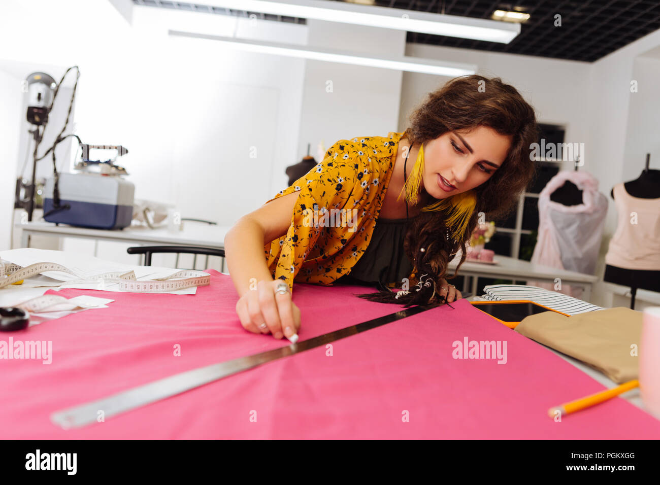 Professional dressmaker drawing straight lines and looking concentrated ...