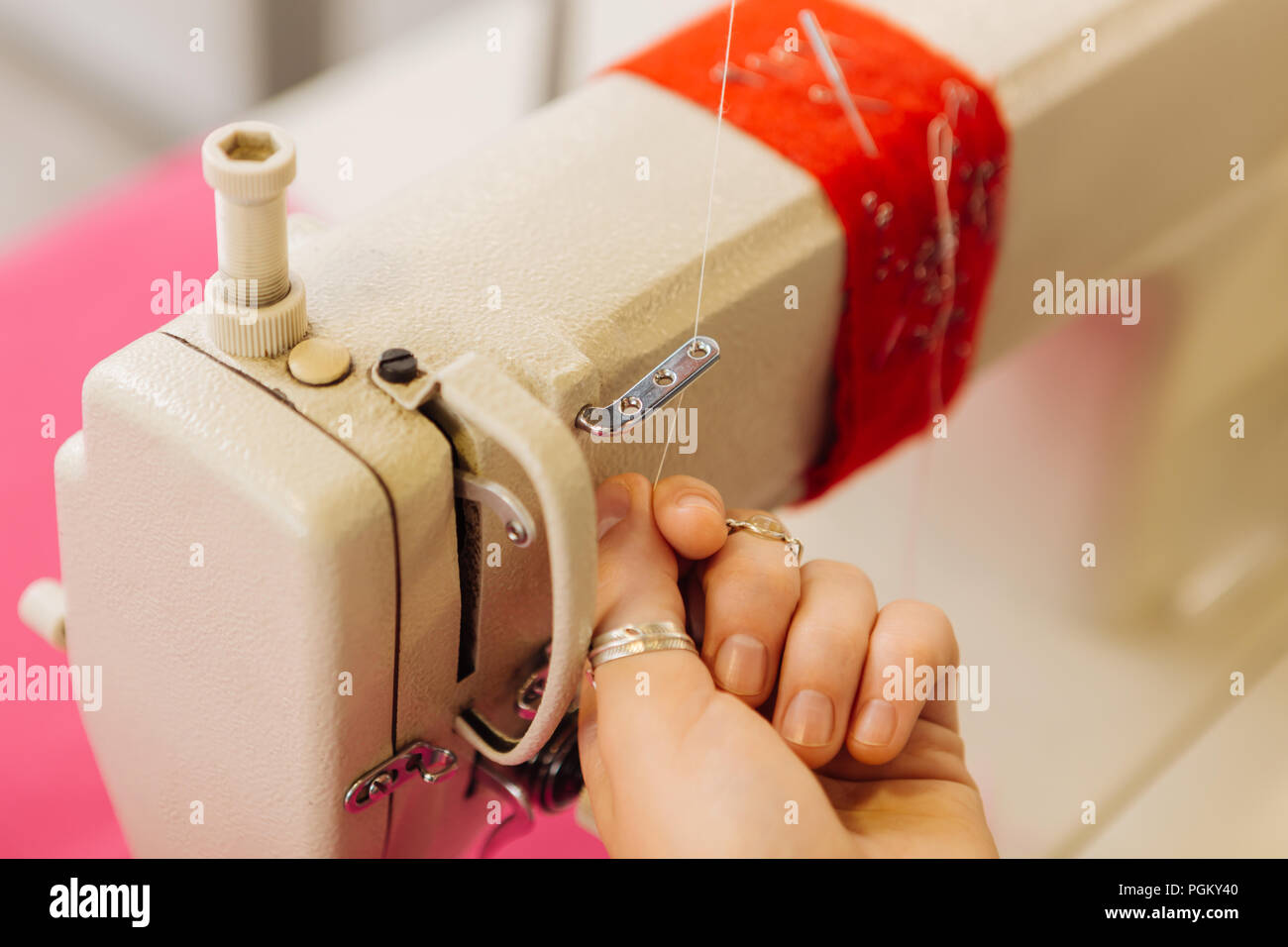 Careful dressmaker holding thread while working with sewing machine ...