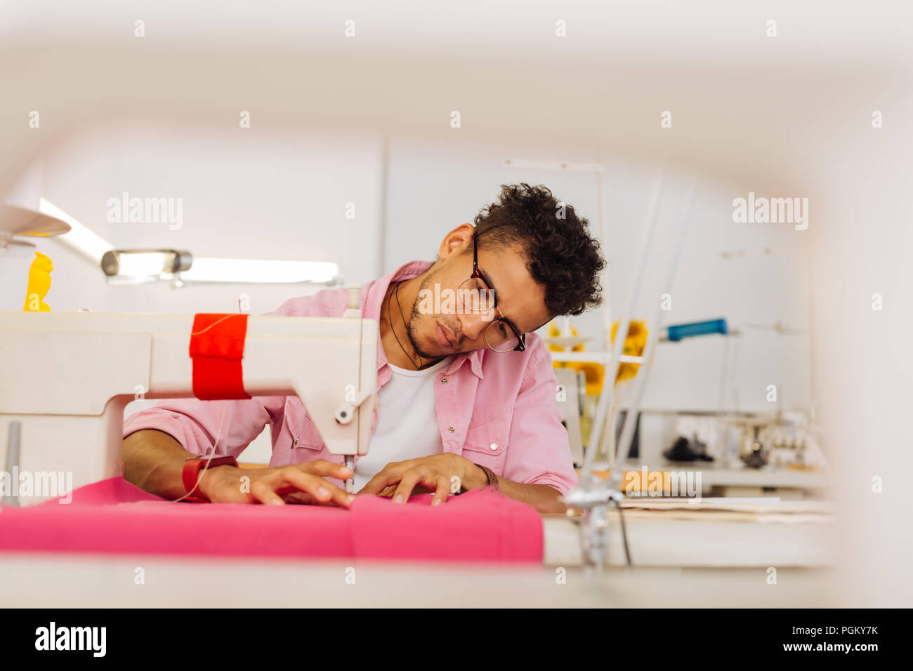 Serious young man leaning his head while using the sewing machine Stock ...