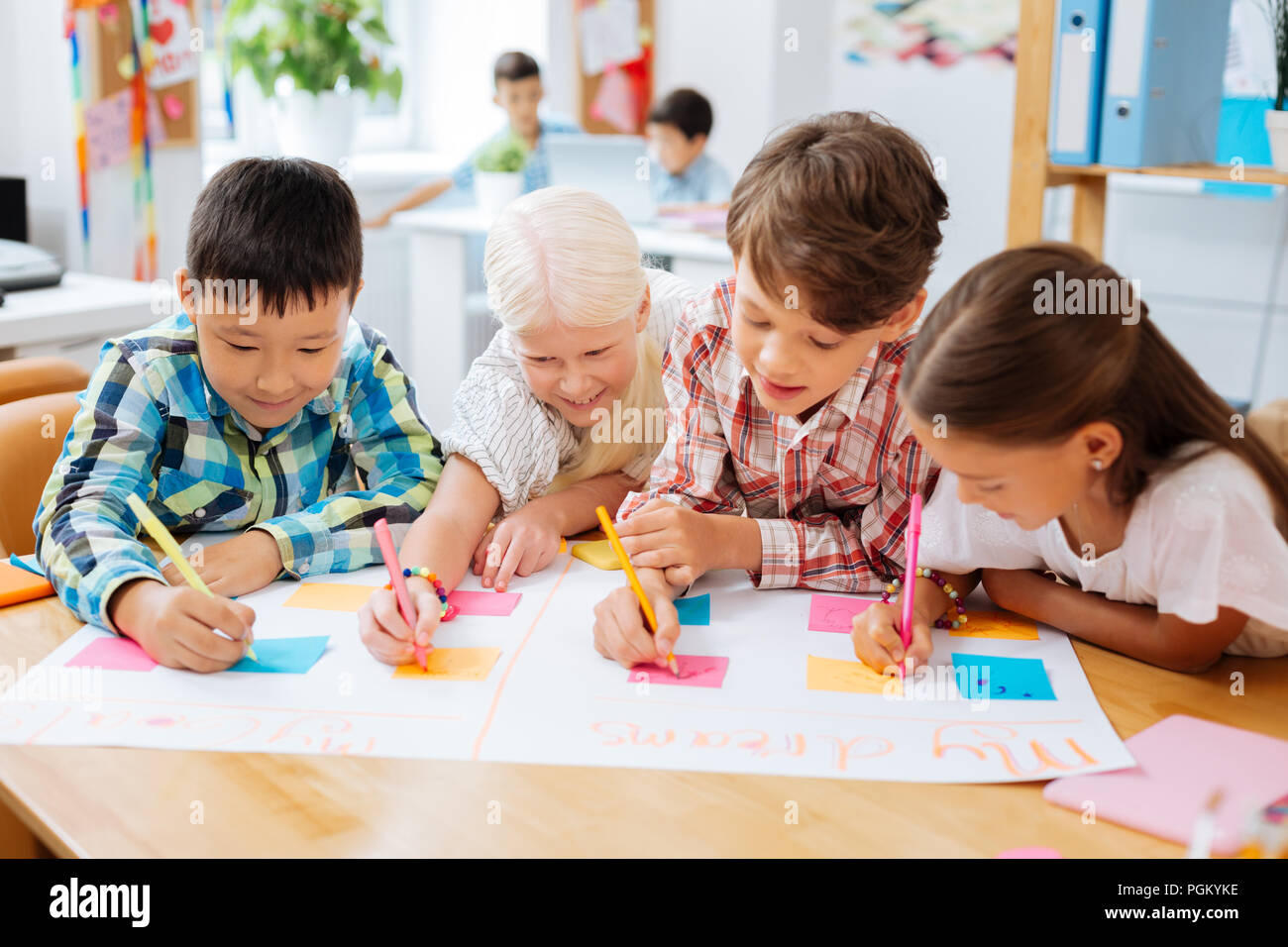 High-spirited children drawing a poster in a classroom Stock Photo - Alamy