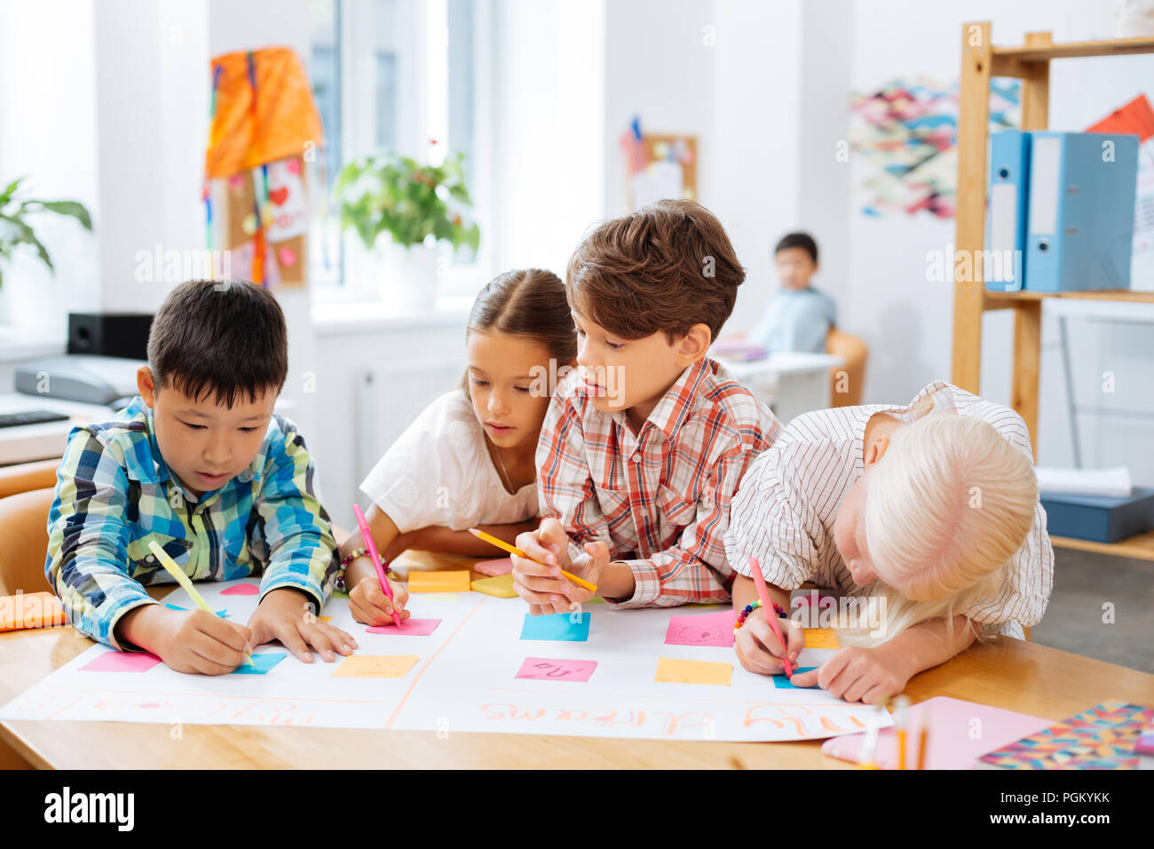 Cute kids drawing a new poster in a classroom Stock Photo - Alamy