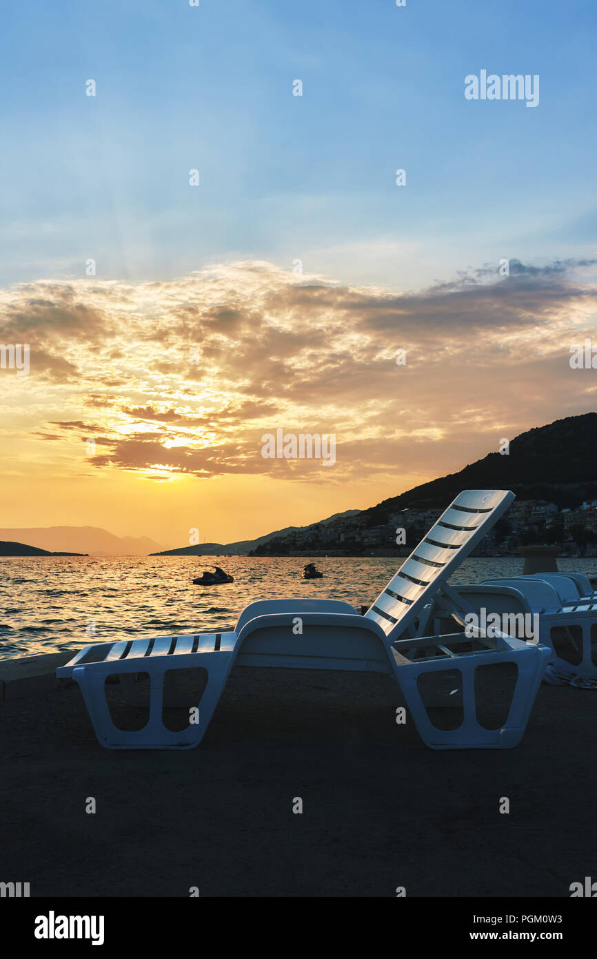 Empty plastic beach lounge chairs with beautiful sunset in background ...
