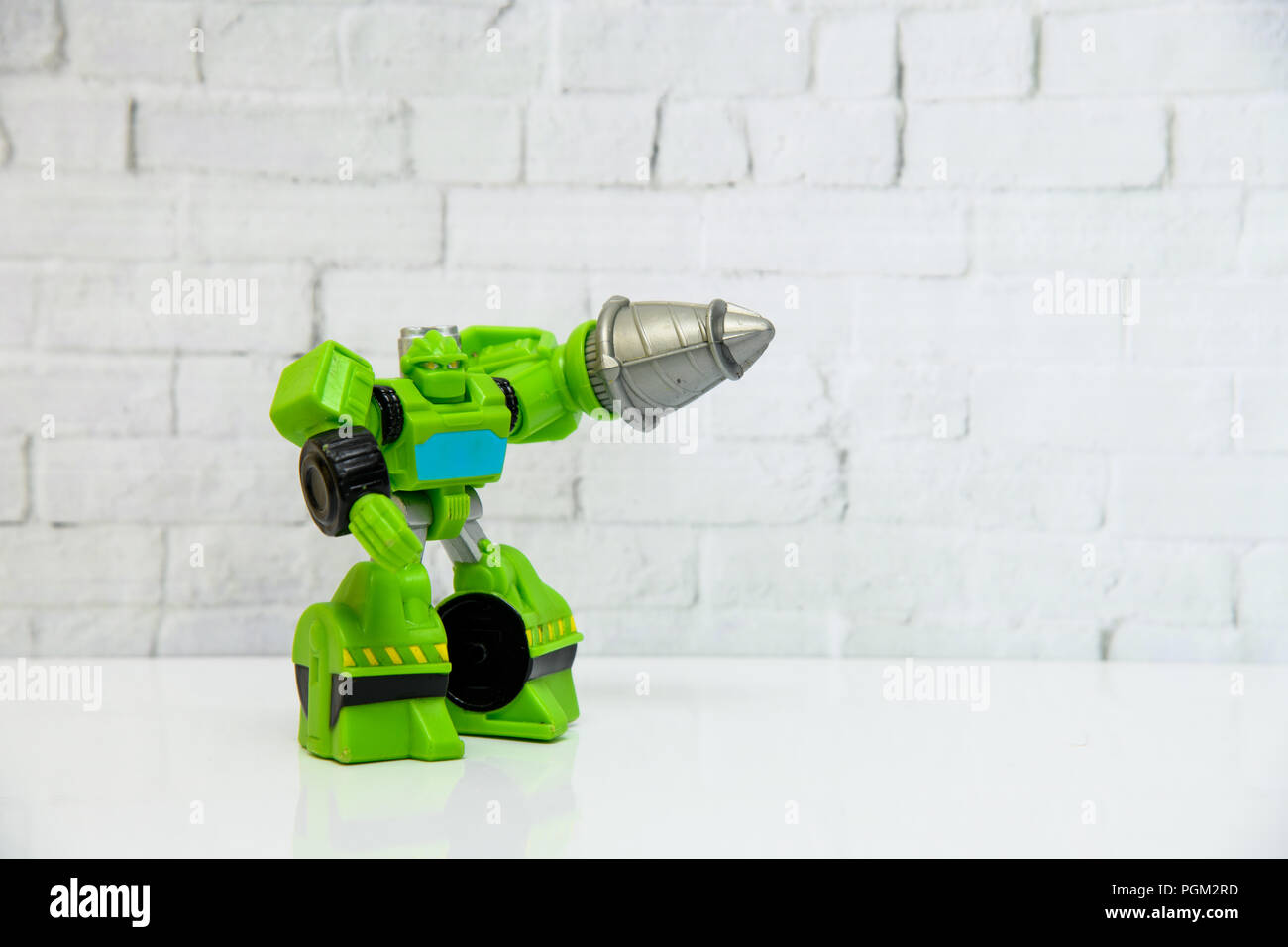 Green plastic kids toy robot on a white reflective shelf Stock Photo ...