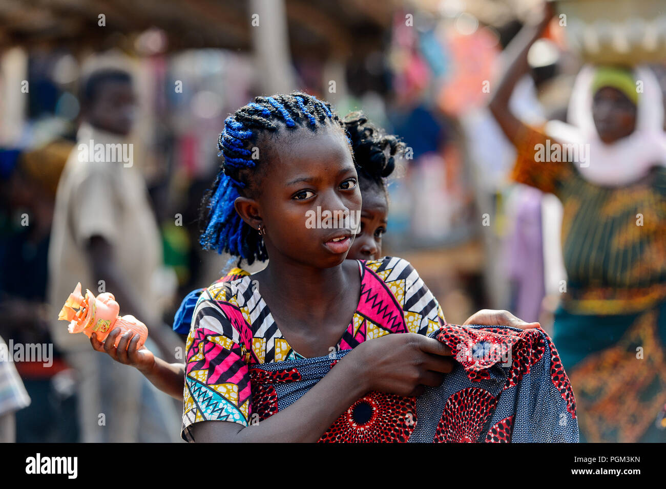 BOHICON, BENIN - JAN 12, 2017: Unidentified Beninese woman with braids carries a baby girl on ...