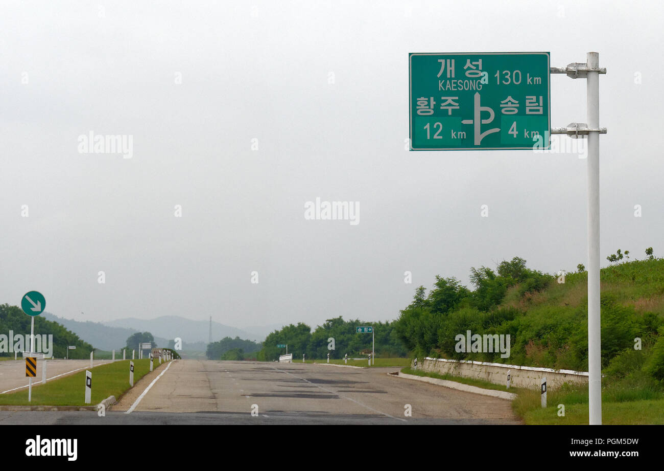 Dual language signpost giving routes to Kaesong, North Korea over an ...