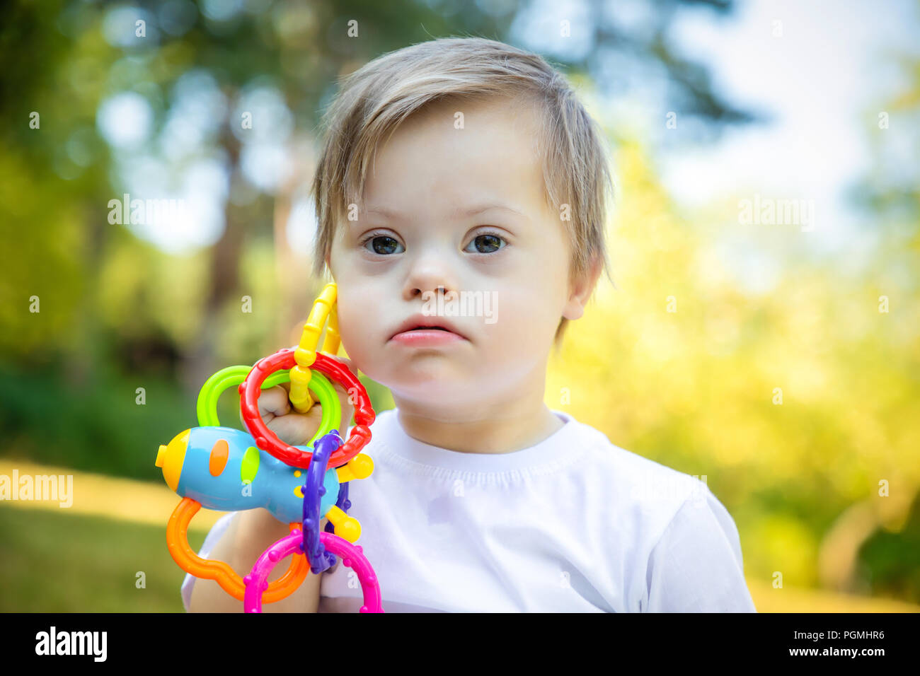 Portrait of Cute small boy with Down syndrome playing in summer day on ...