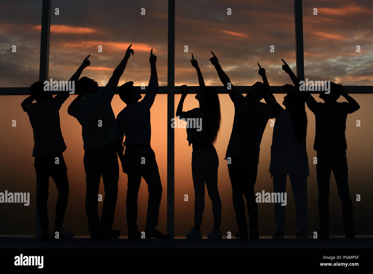 business team pointing through a large office window to blank space ...