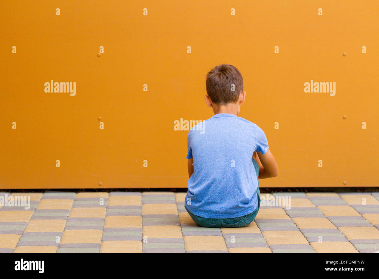 Sad alone boy sitting near colorful wall outdoors Stock Photo - Alamy