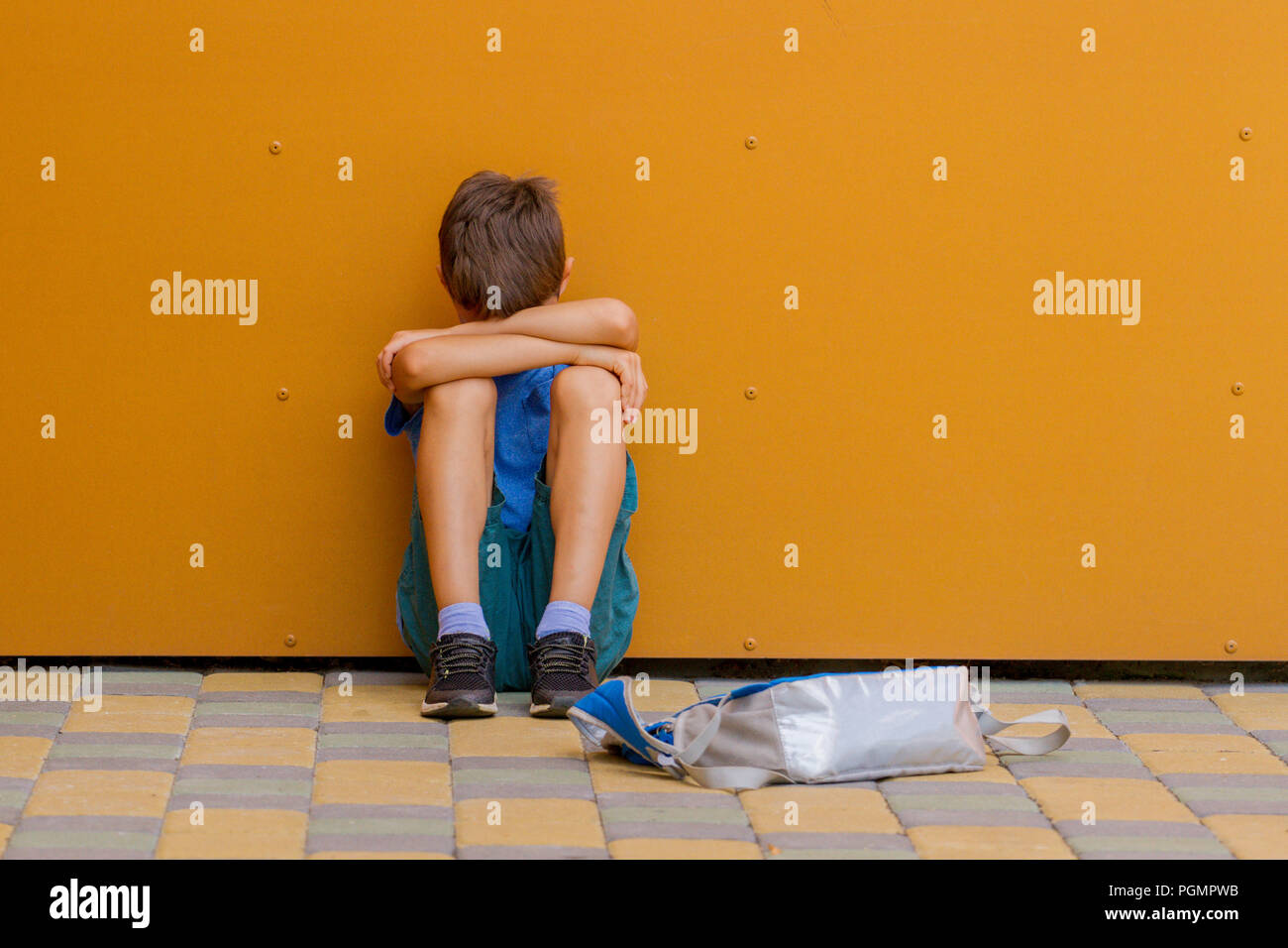 Sad alone boy sitting near colorful wall outdoors Stock Photo - Alamy