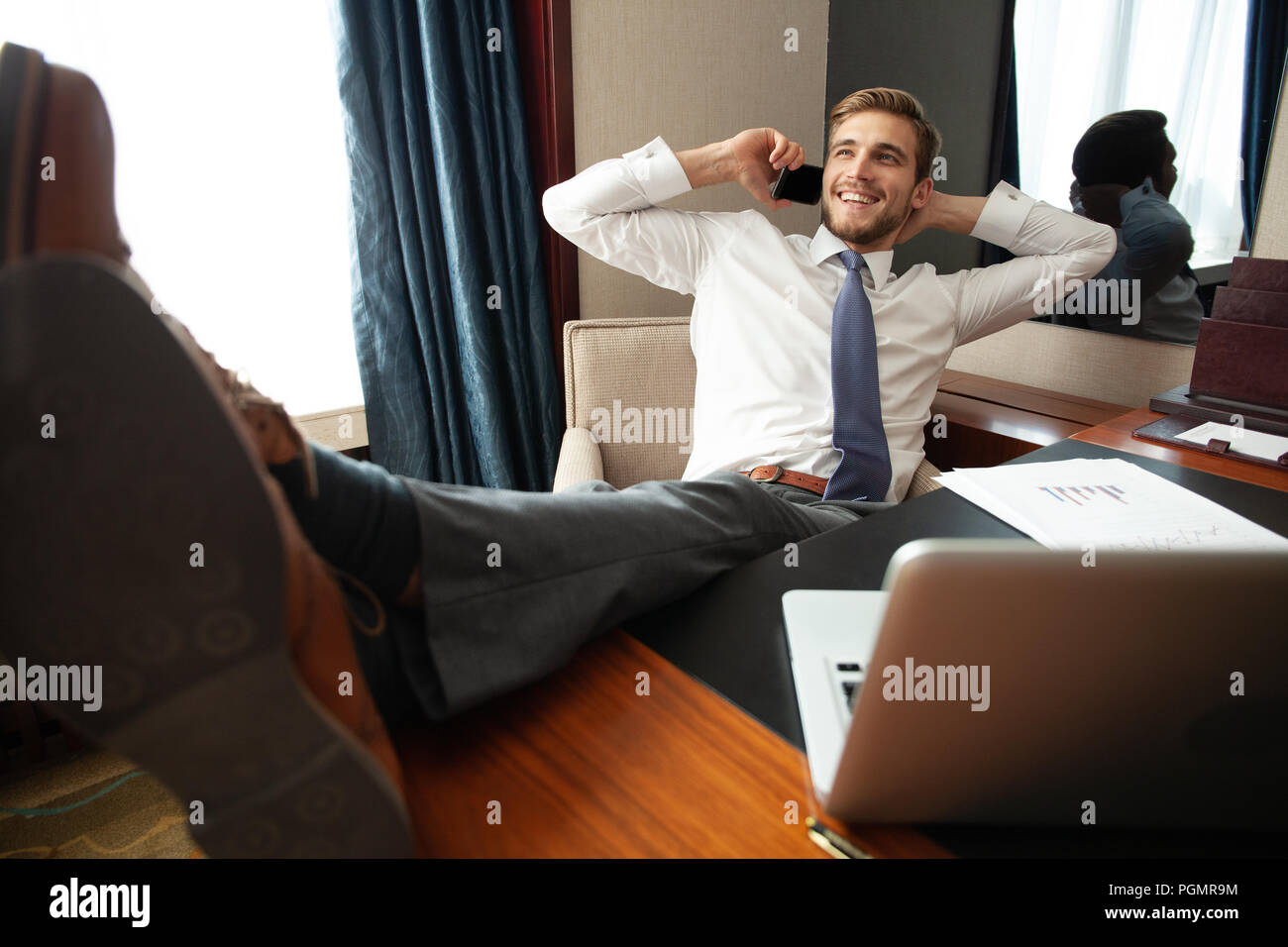 Portrait of handsome young entrepreneur speaking by phone and using ...