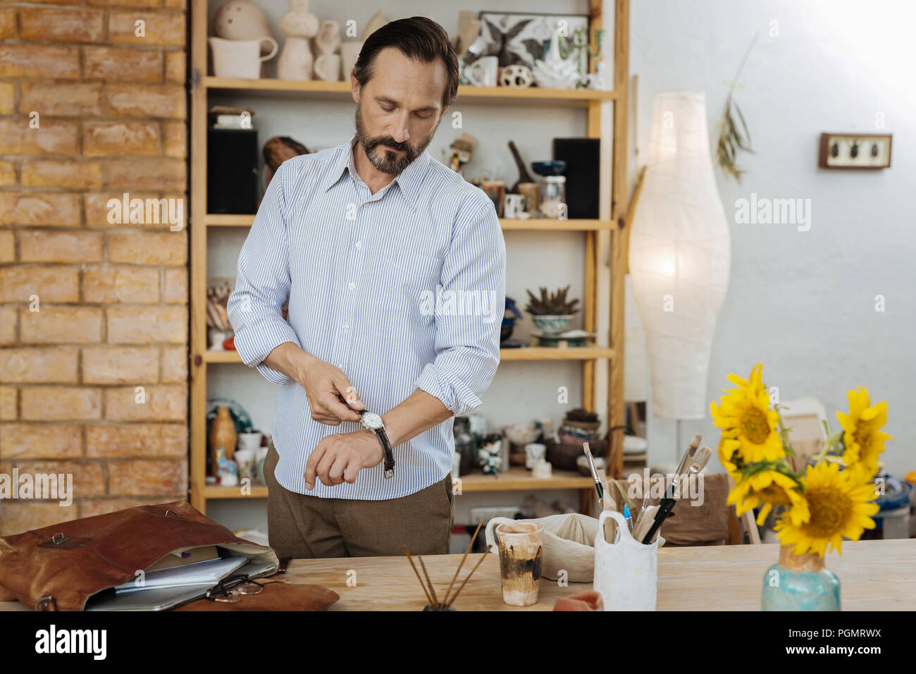 Dark-haired handyman taking off his hand watch preparing for work Stock ...
