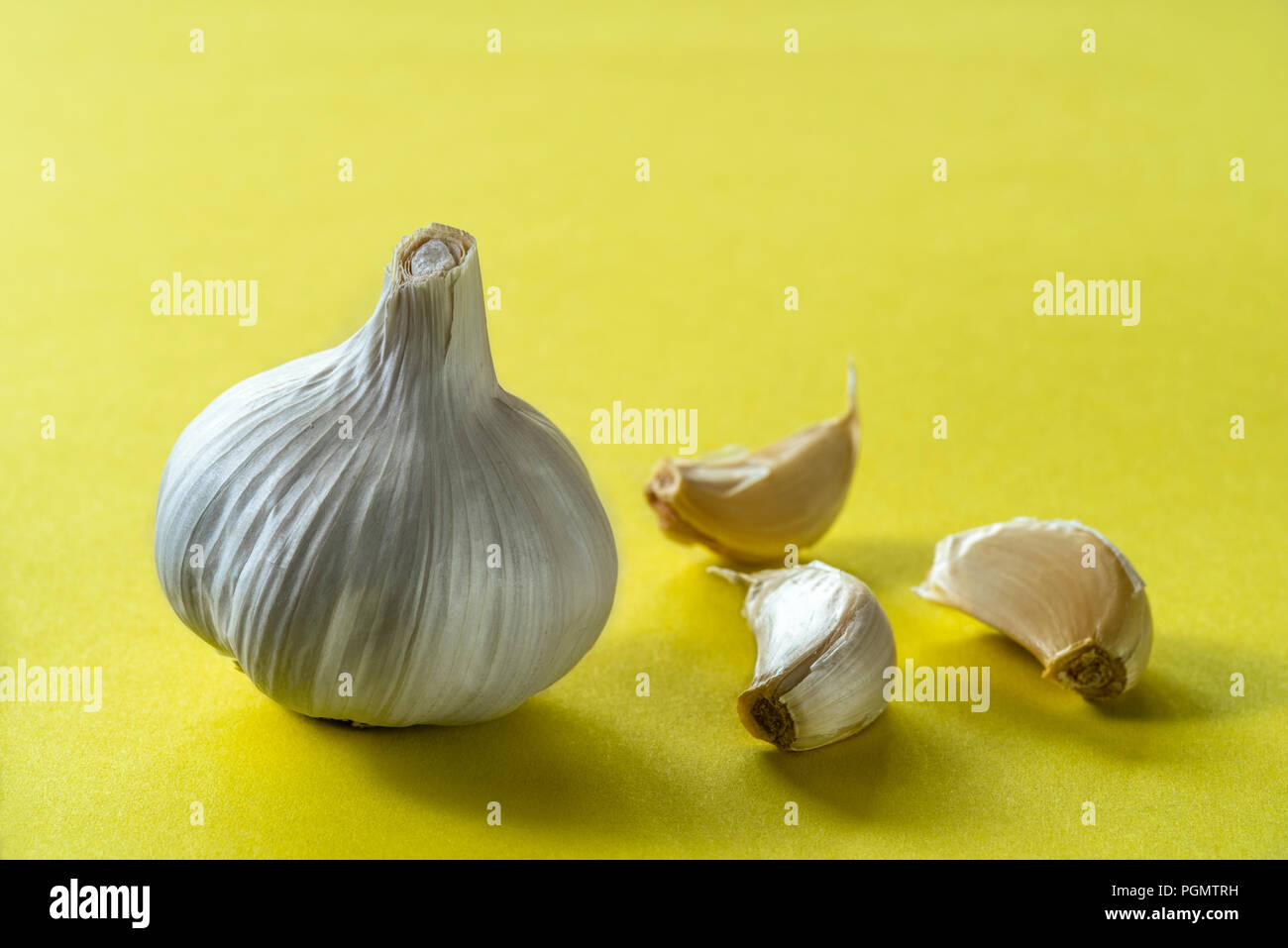 Garlic bulb and cloves on an acid yellow background Stock Photo - Alamy
