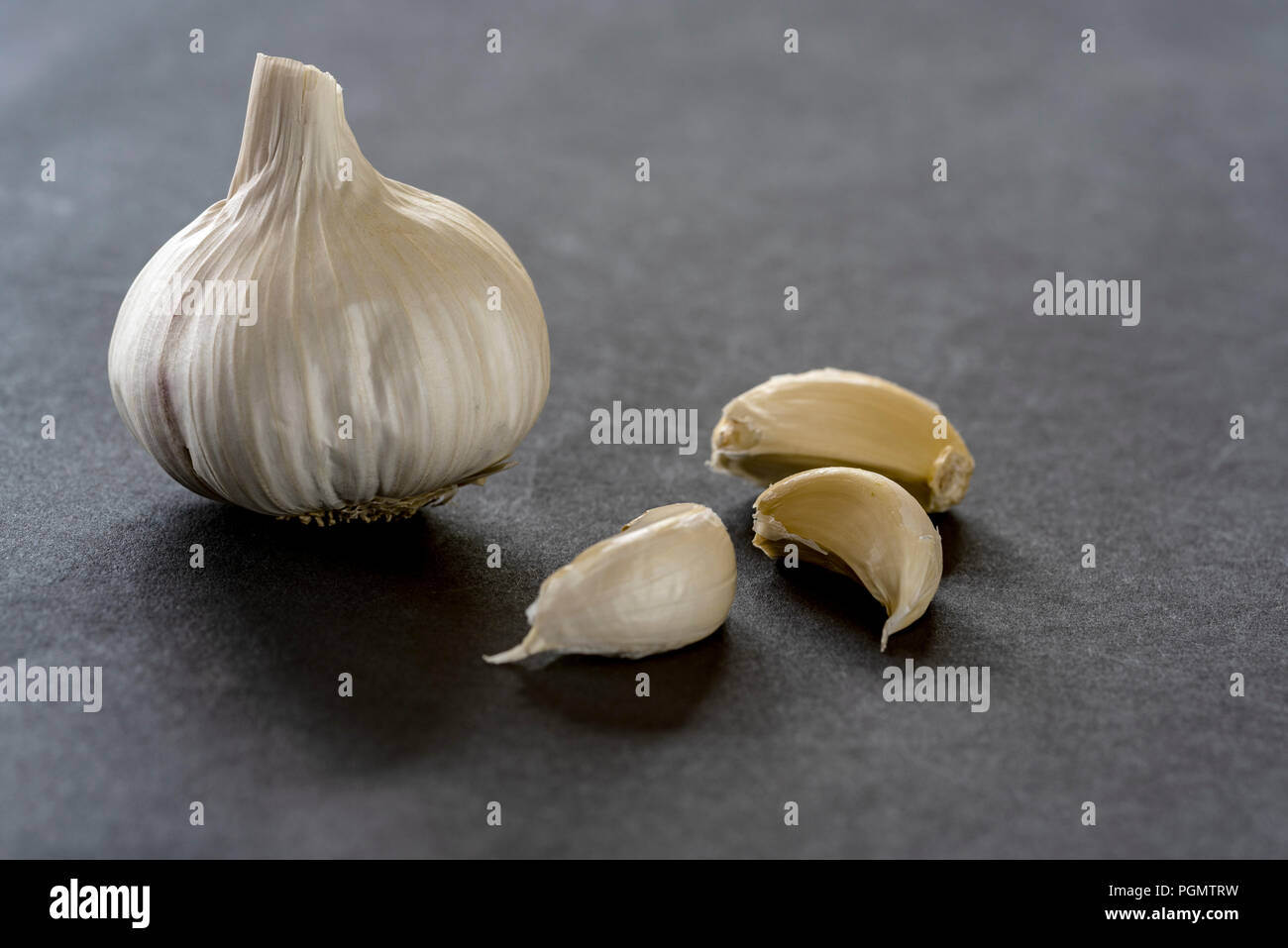 Garlic bulb and cloves on a dark grey background Stock Photo - Alamy