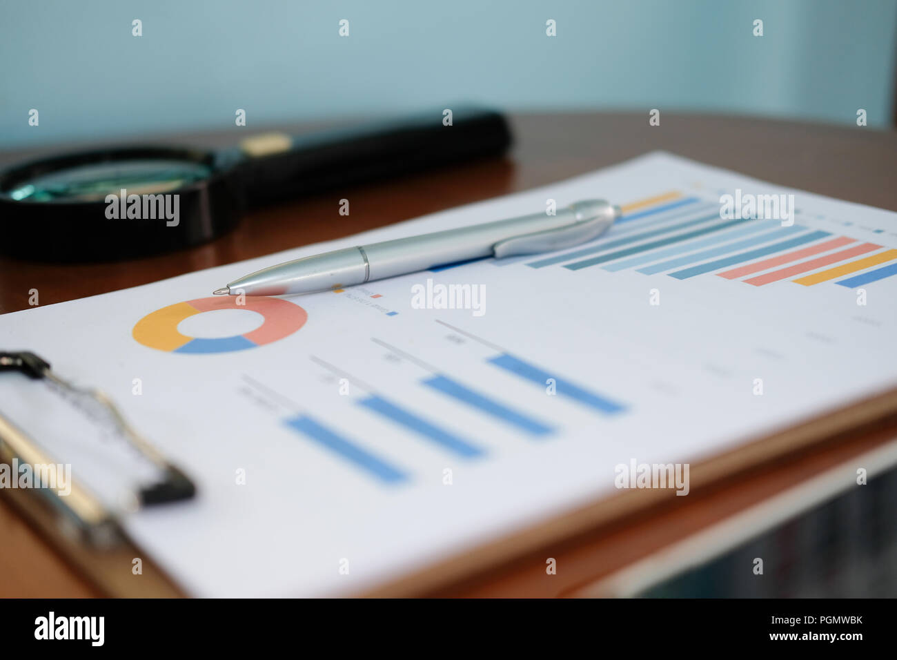 graph chart document, pen & magnifying glass on office table Stock ...