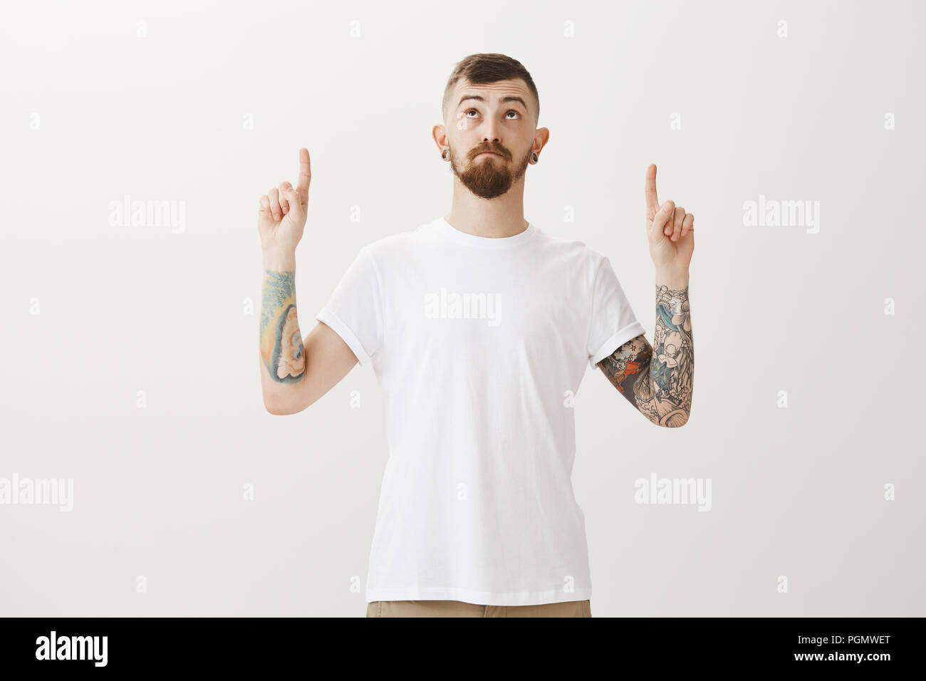 Handsome stylish caucasian urban guy with beard and tattoos, pointing ...