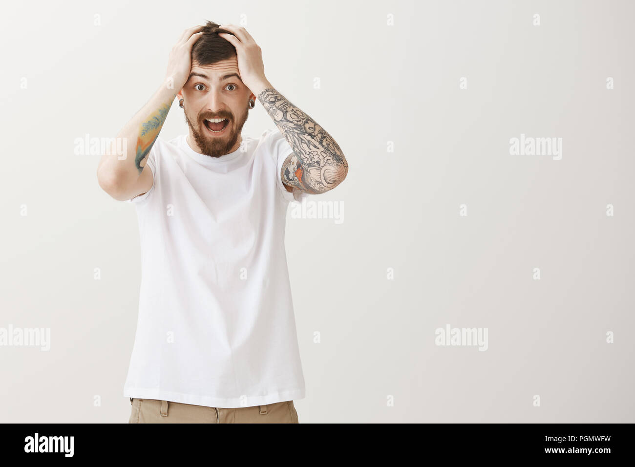 Portrait of handsome adult male model with tattoos on arms, yelling at ...