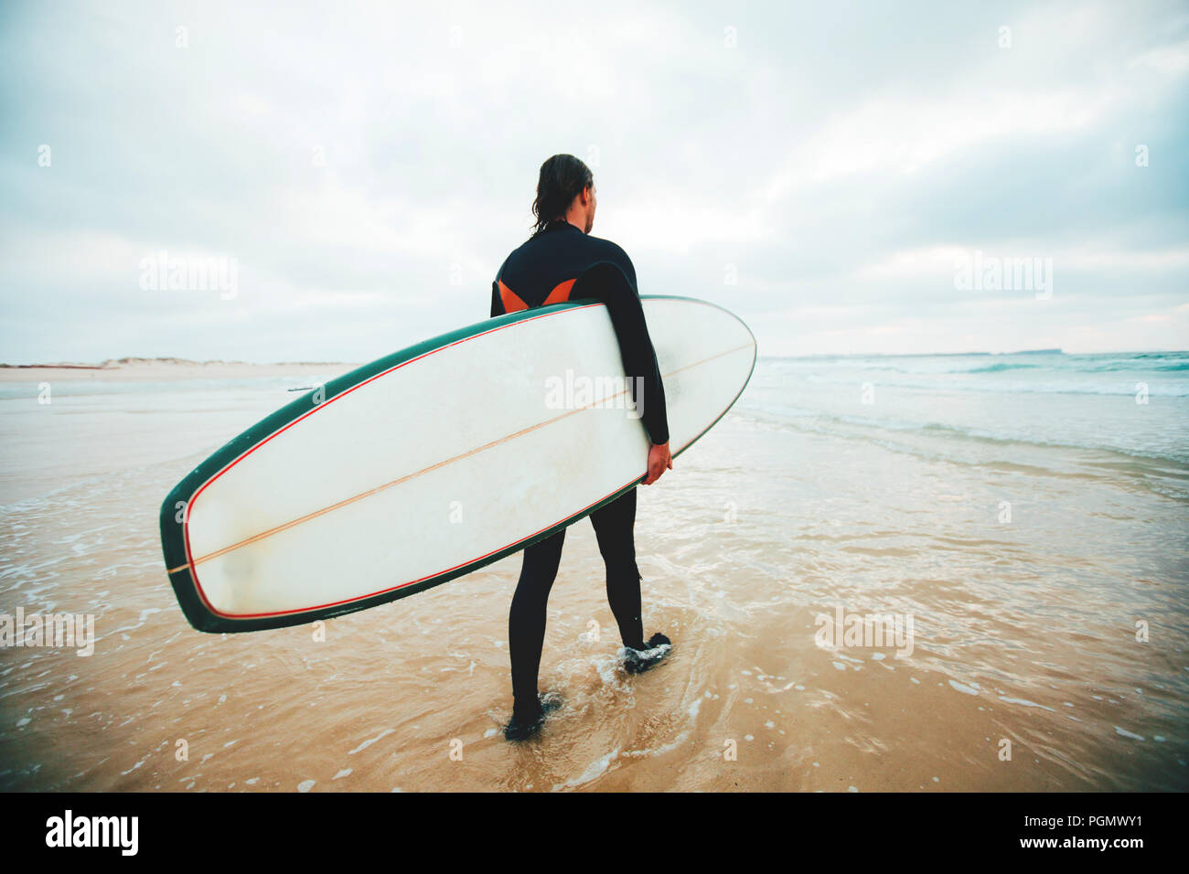 Surfer with surfboard goes to the ocean Stock Photo - Alamy