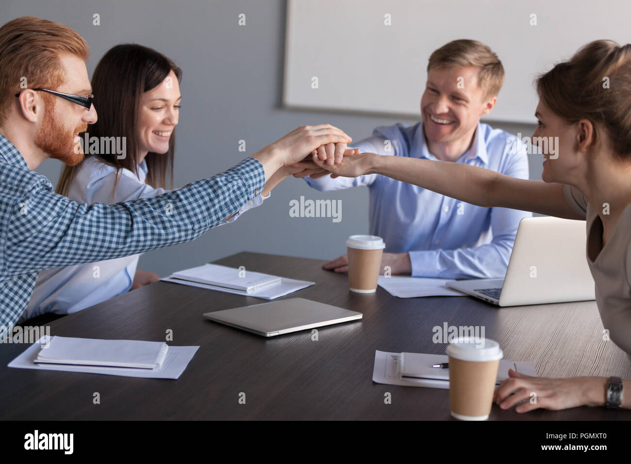 Excited workers join hands engaged in teambuilding activity Stock Photo ...