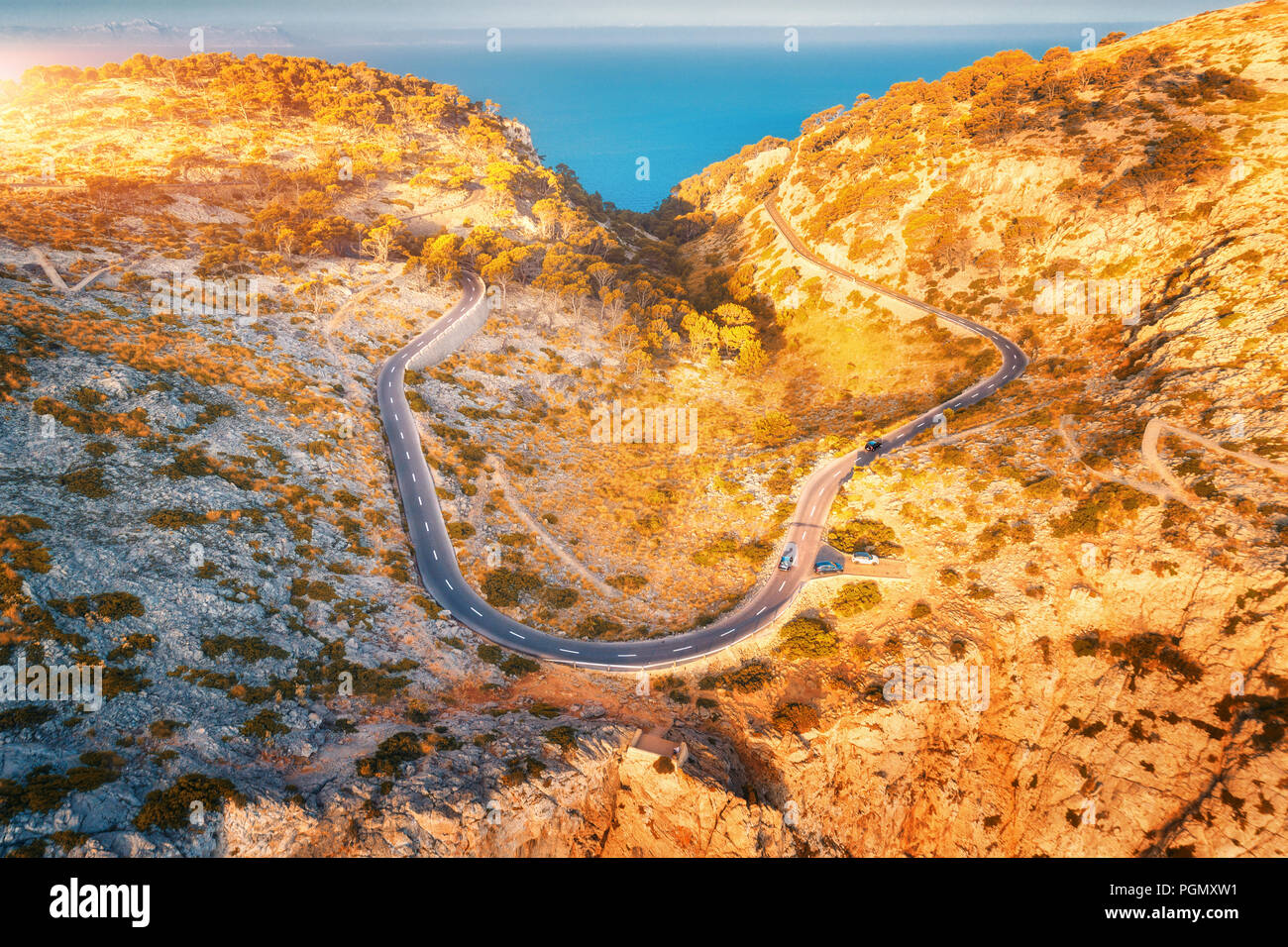 Aerial view of mountain curve road with cars, orange forest at sunset ...