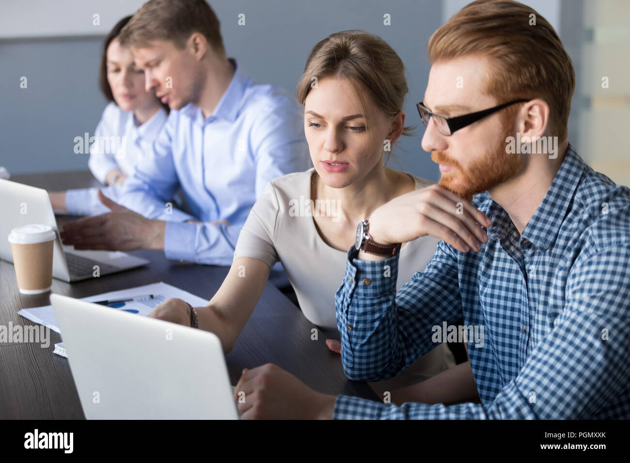 Concentrated workers busy at laptops discussing business project Stock ...