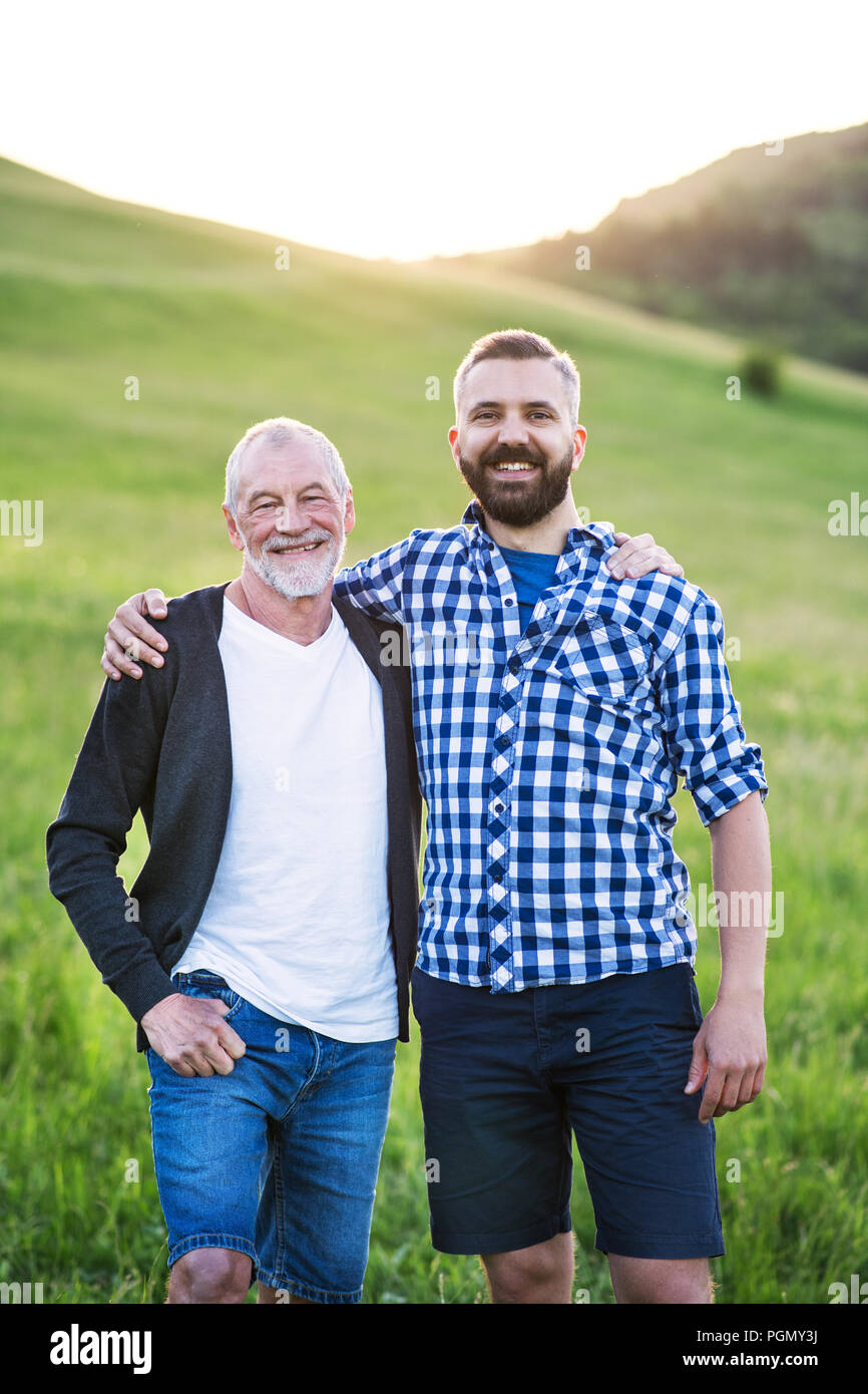 A Portrait Of A Laughing Adult Hipster Son With Senior Father In Nature
