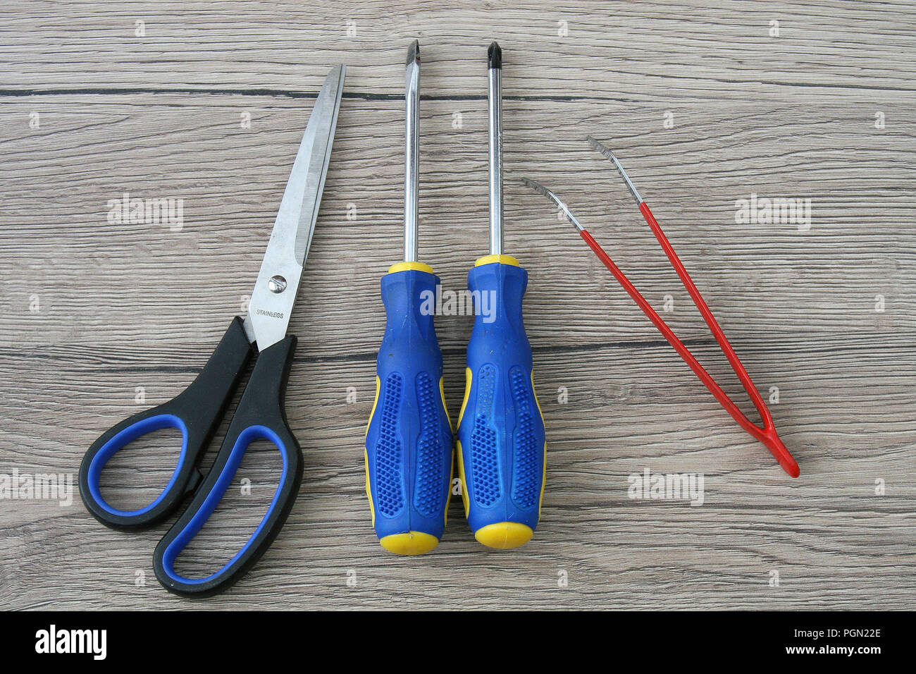 Scissor, Screwdriver and Tweezers Isolated on Gray Wooden Desk Stock ...