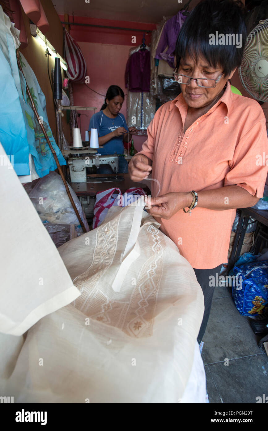 A modiste sews buttons onto a Barong Tagalog shirt inside Cress Lontoc ...