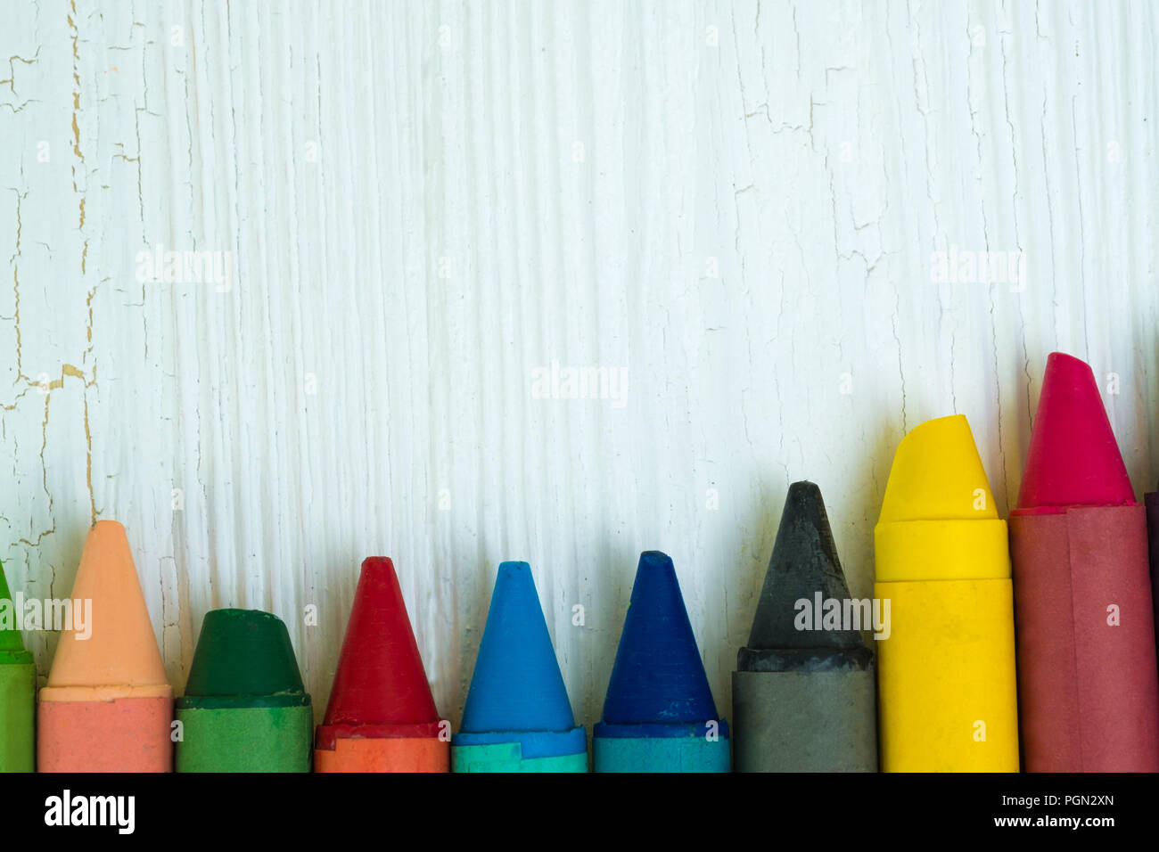 Colourful wax crayons pencils on white wood table with copy space for ...