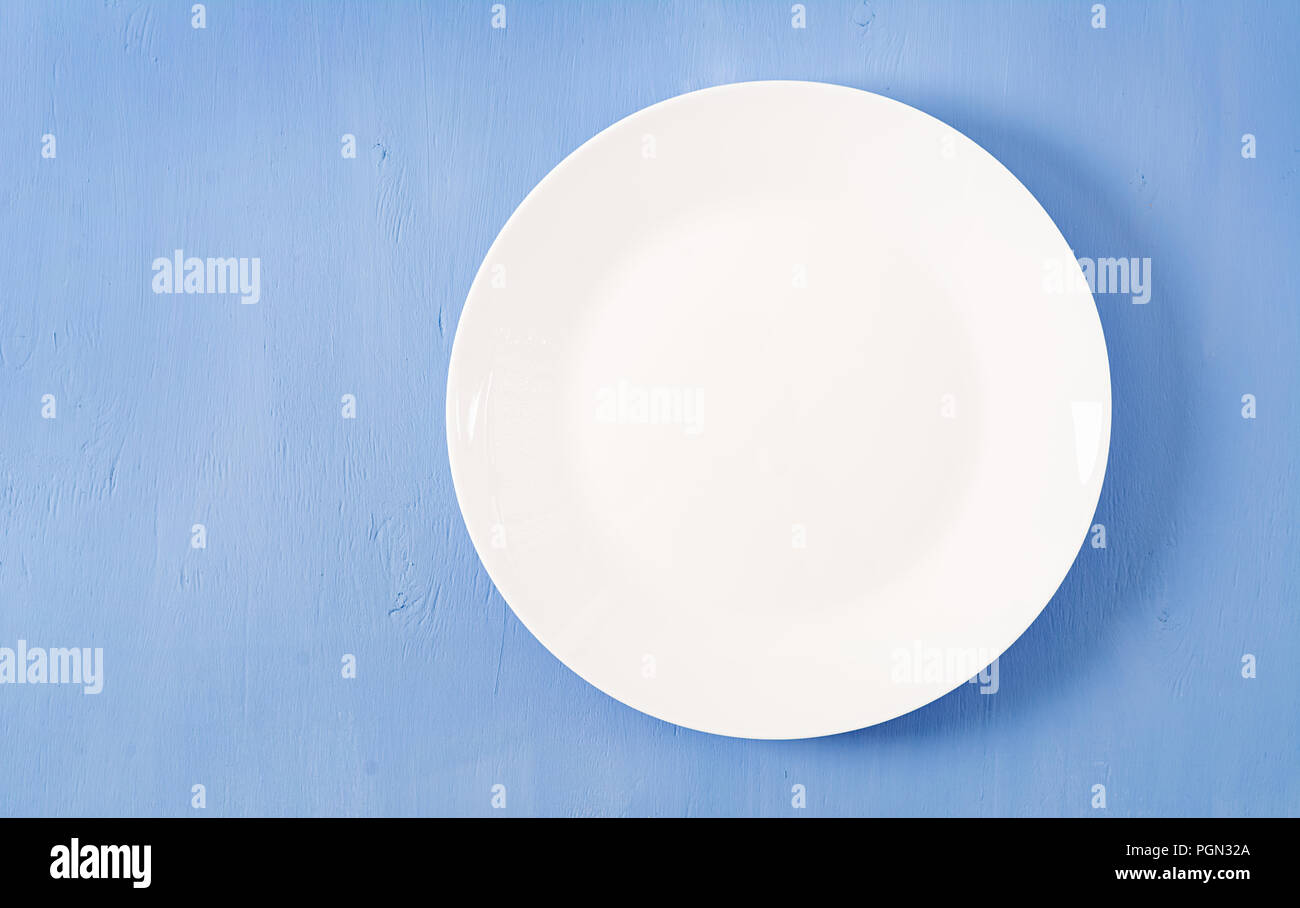 Top view of blank white dish on a blue background. Copy space. Mockup ...